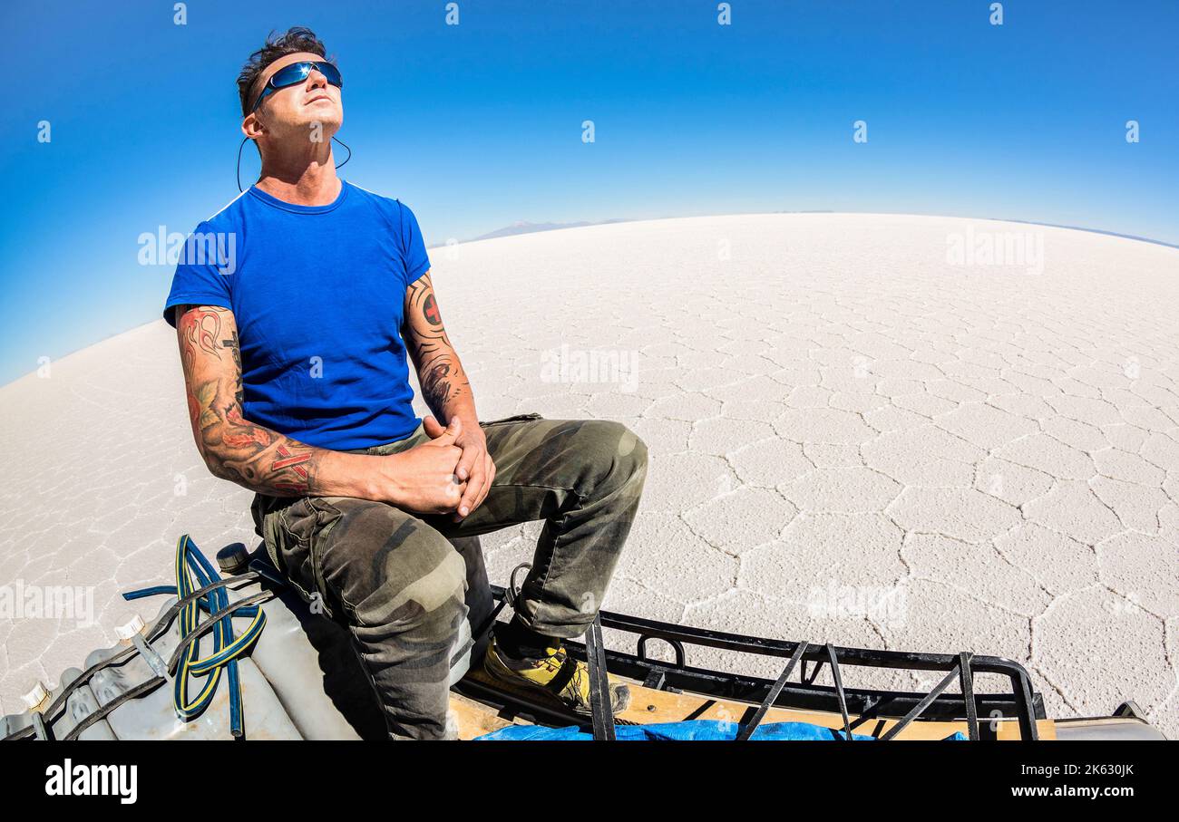 Young man solo traveler taking relax break at Salar de Uyuni saltflats ...