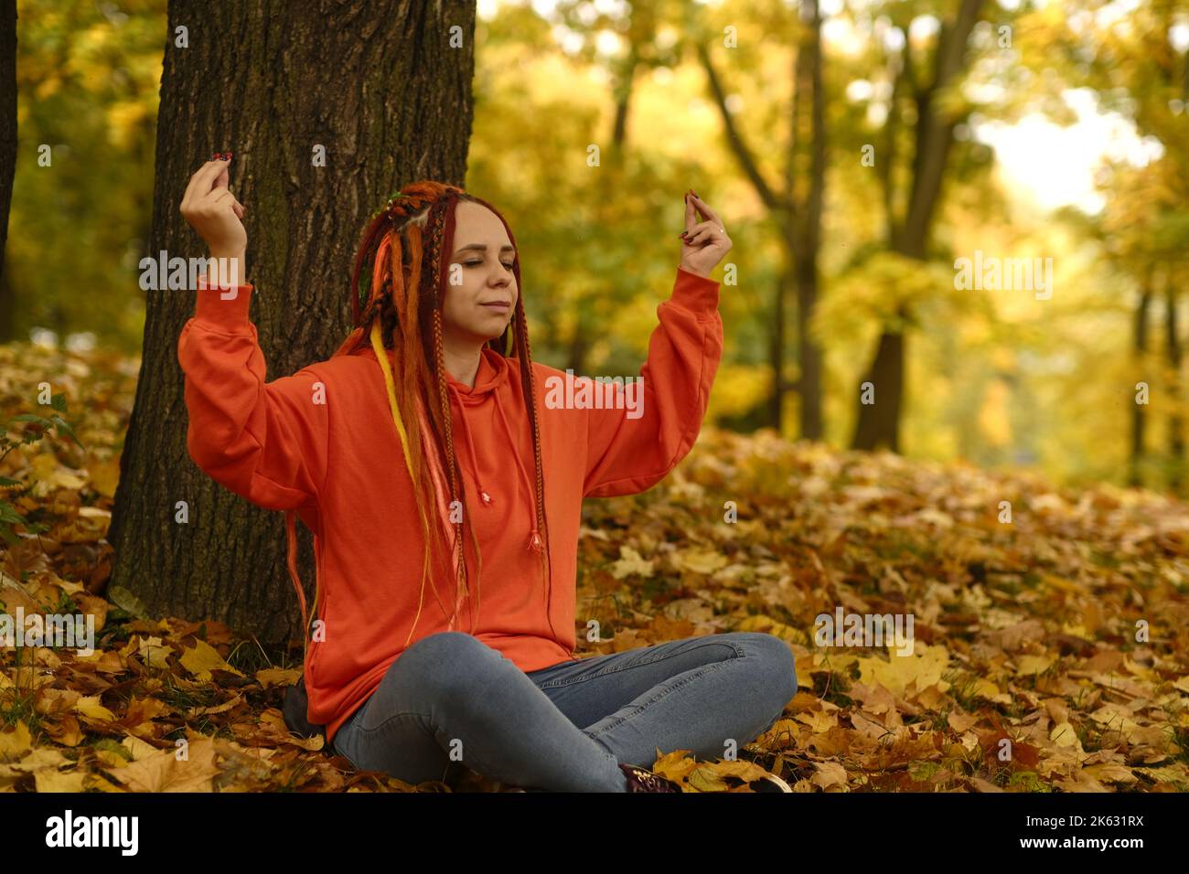 Young woman with dreadlocks meditating with closed eyes, sitting near ...