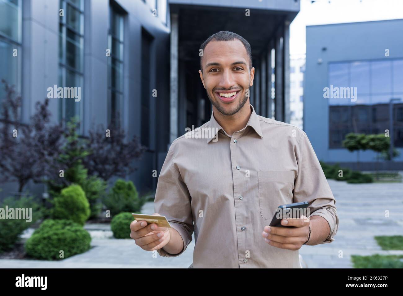 Portrait of happy hispanic man outside office building looking at ...