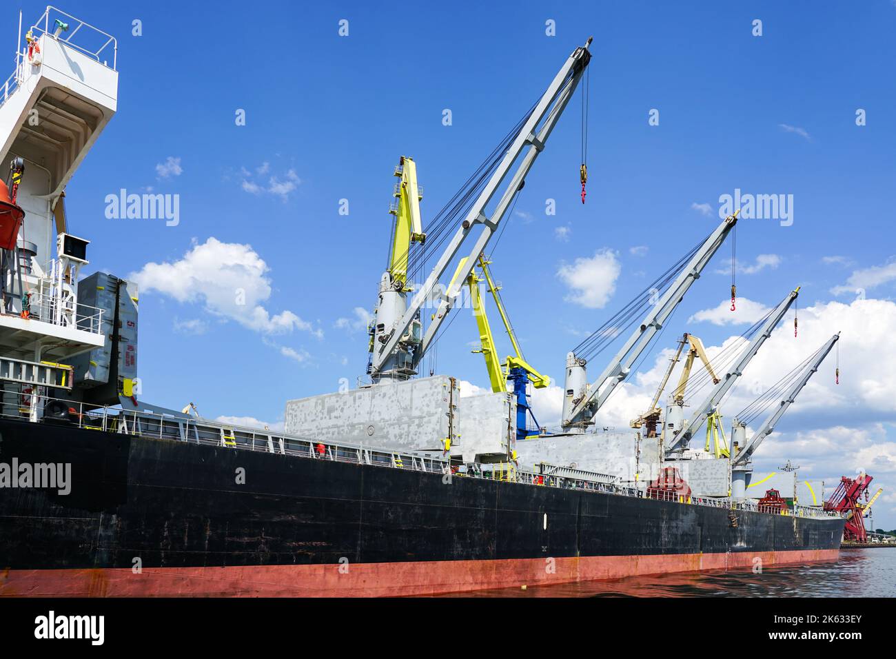 Large bulk carrier with open holds in harbor cargo terminal, shore ...