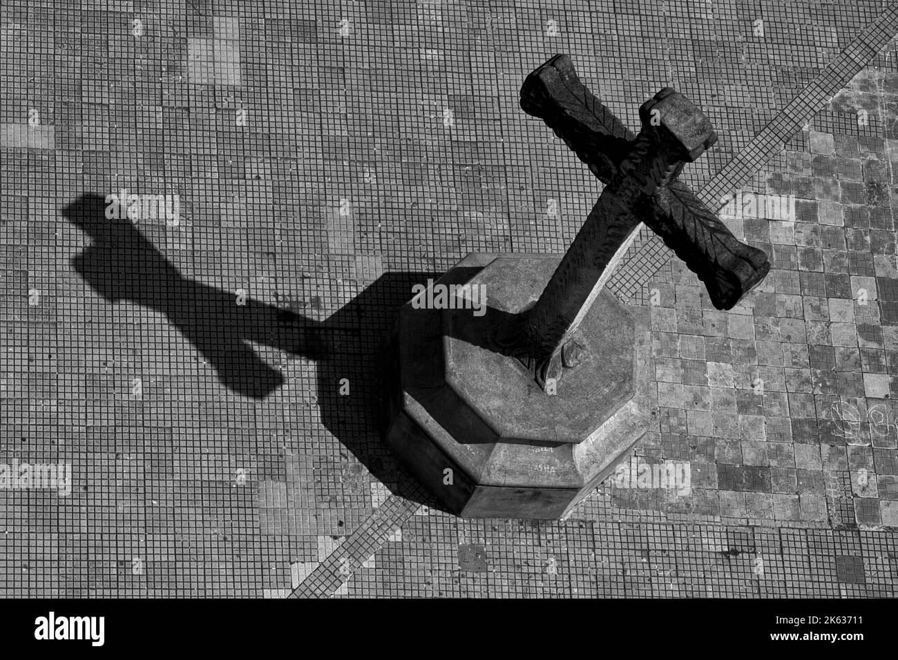 A grayscale of a cross statue on the street Stock Photo - Alamy