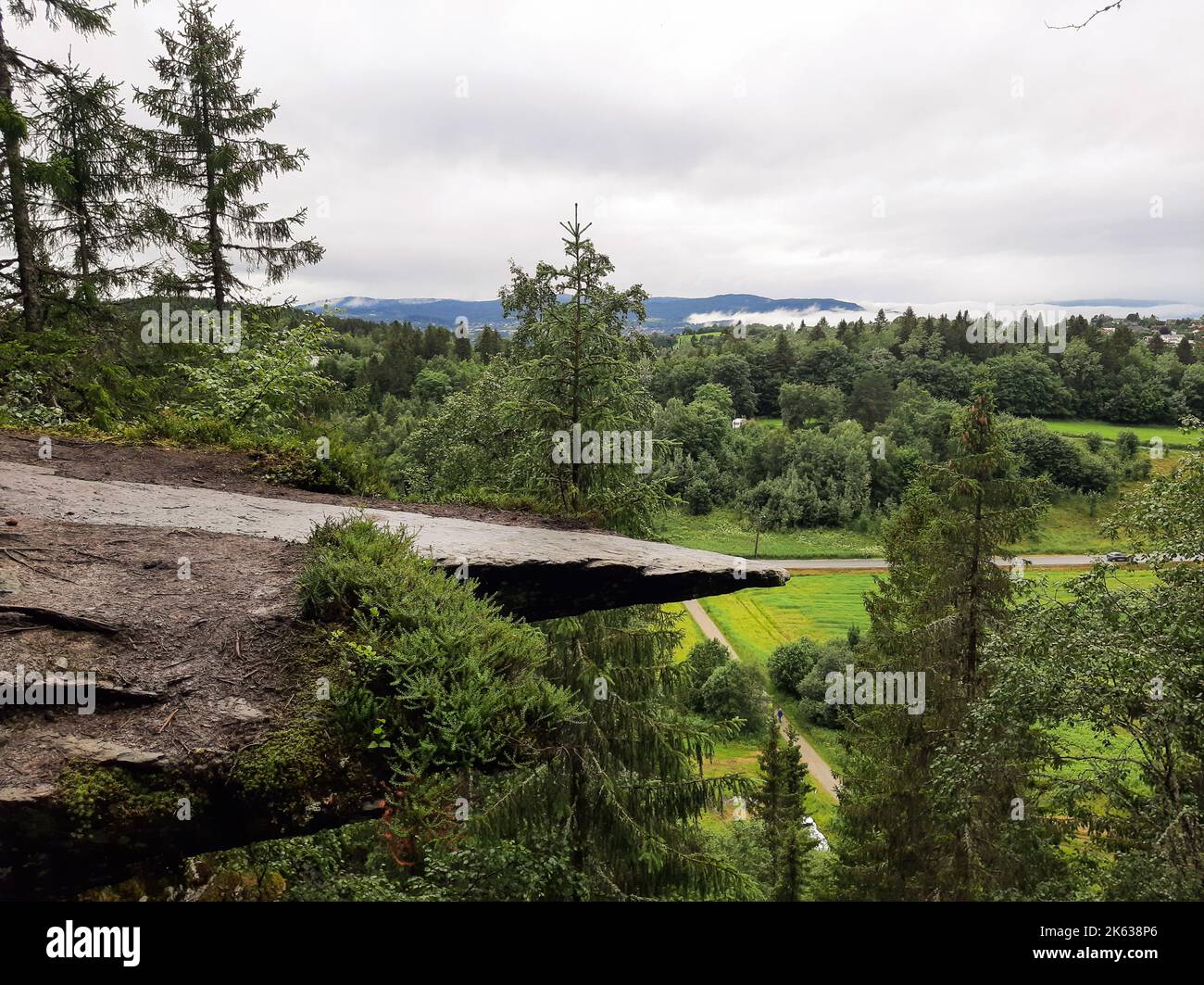 A rock projection extending outwards on top of a hill overlooking green ...