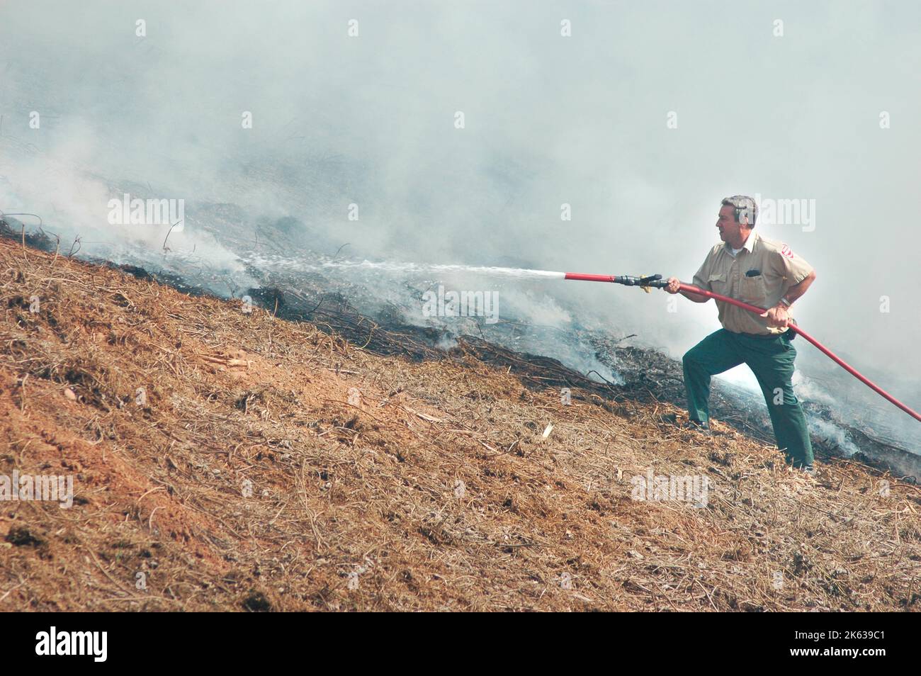 Firemen fighting a small brush fire in the Atlanta area with water and ...