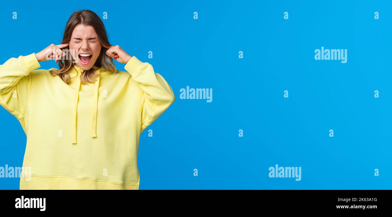 Annoyed and disturbed bothered blond woman shut ears and scream as hear ...