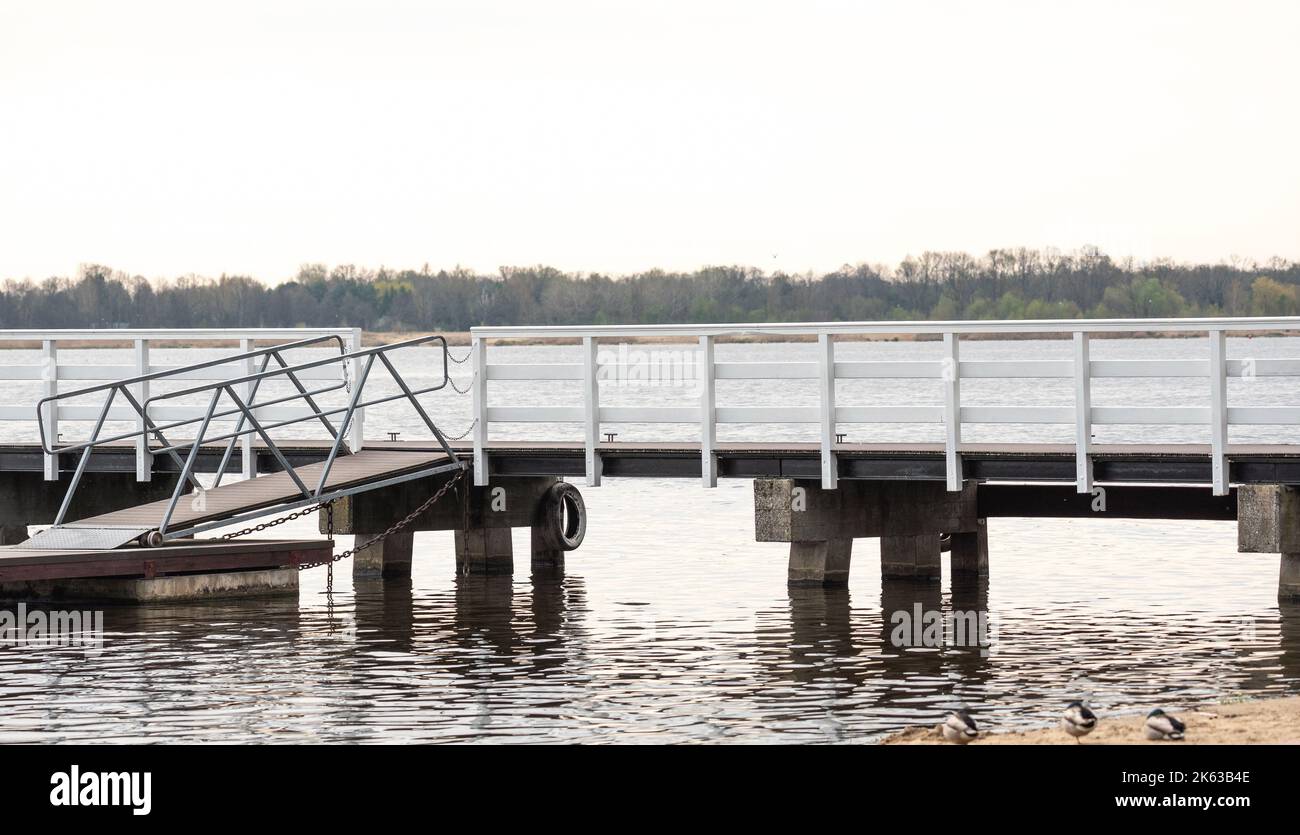 A white wooden pier over the water. Wooden structure on the beach by ...
