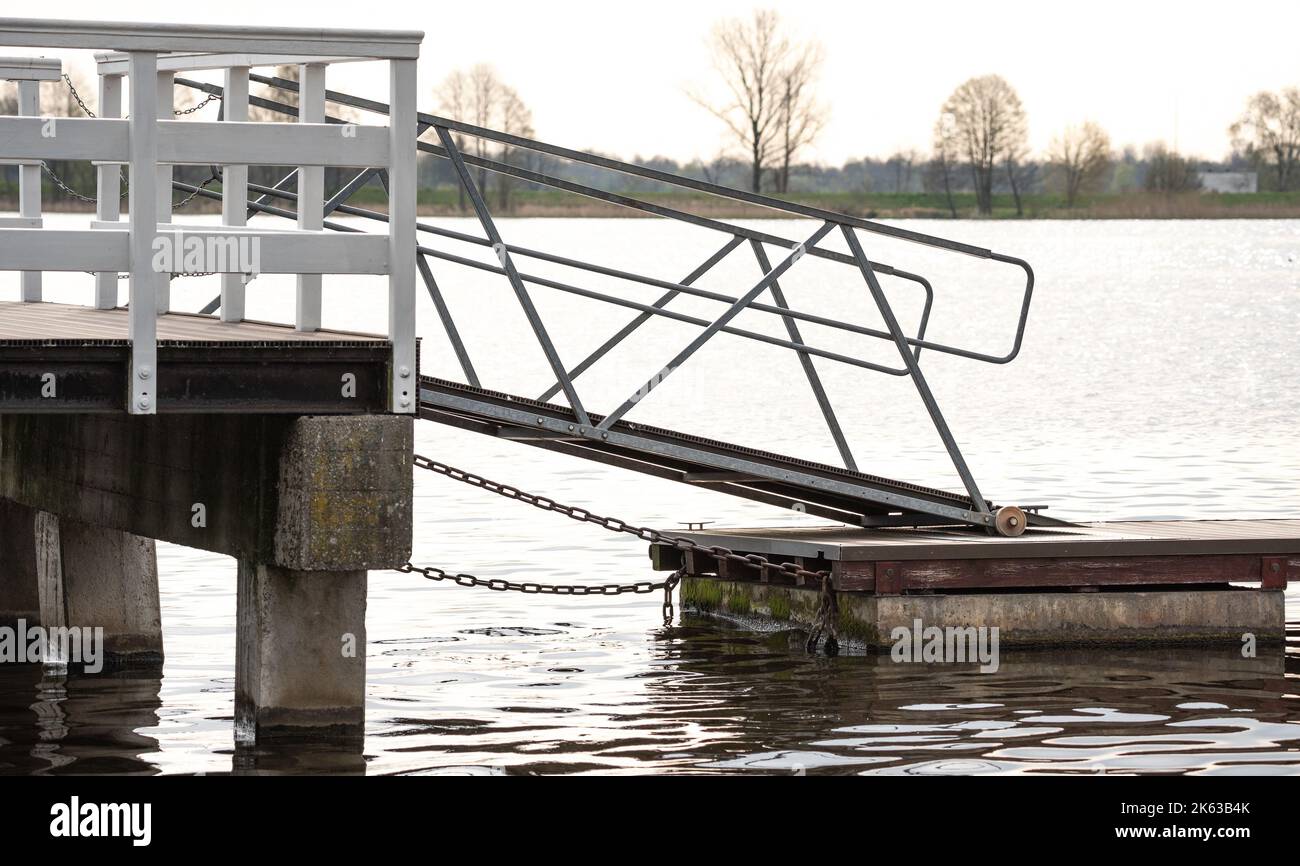 A white wooden pier over the water. Wooden structure on the beach by ...