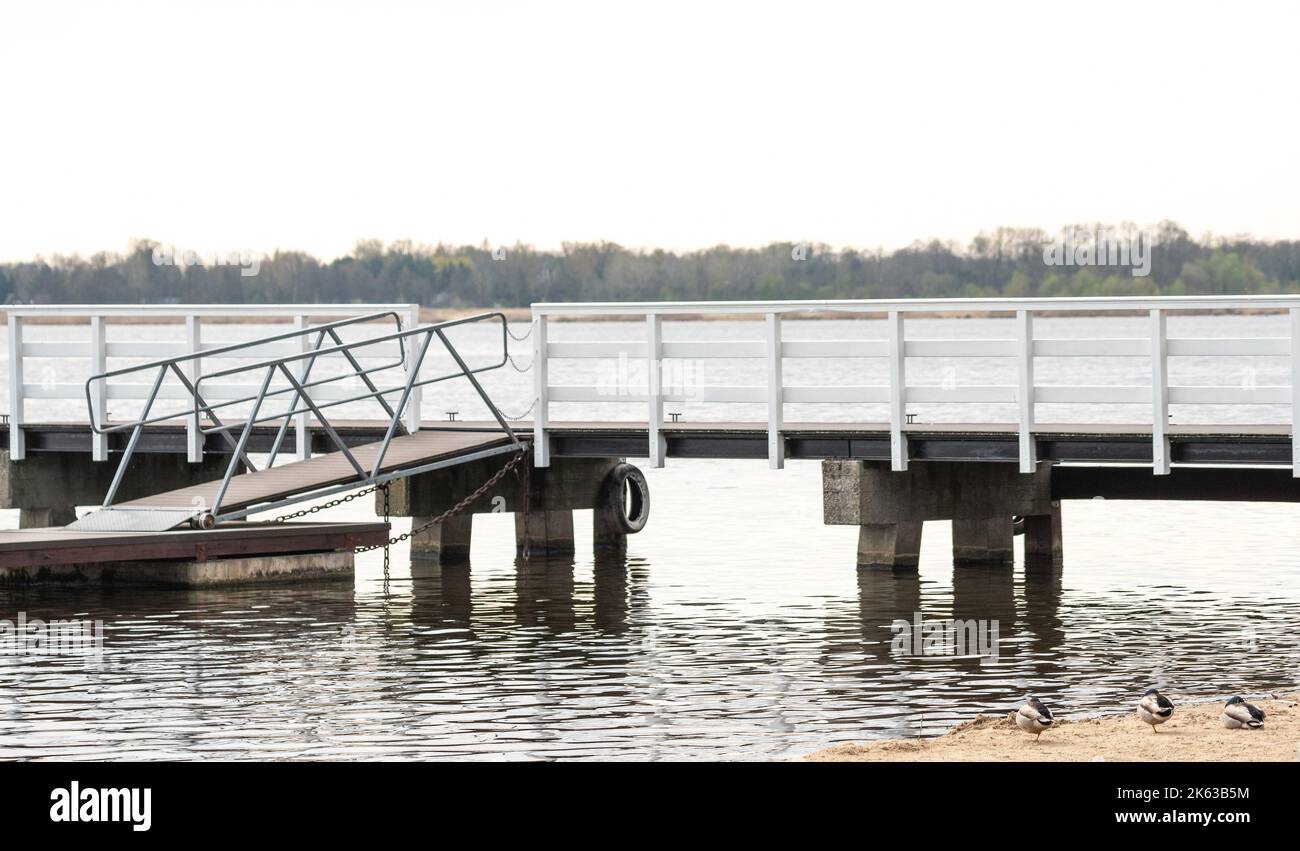 A white wooden pier over the water. Wooden structure on the beach by ...
