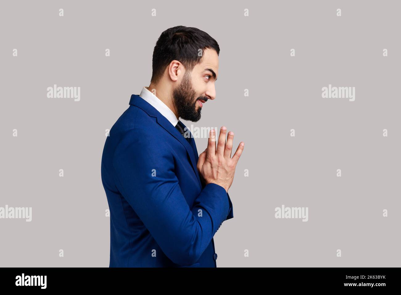 Side view of cunning bearded man clasping hands and planning evil ...