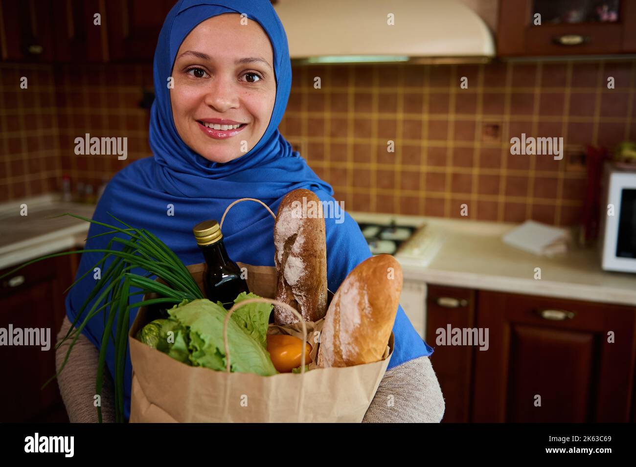 Young Arab Muslim woman with head covered in blue hijab, unpacking ...