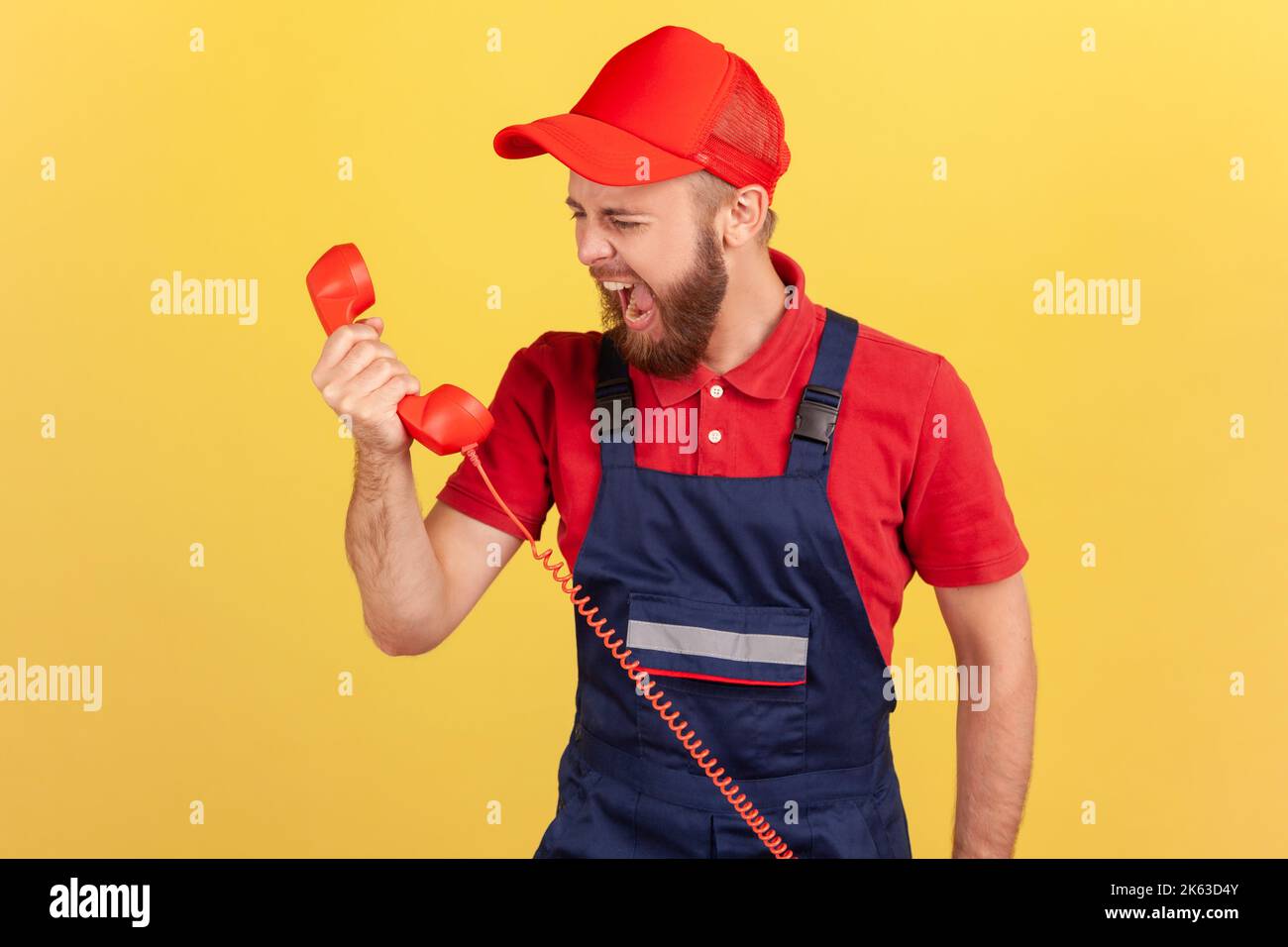 Portrait of angry aggressive worker wearing blue overalls screaming to ...