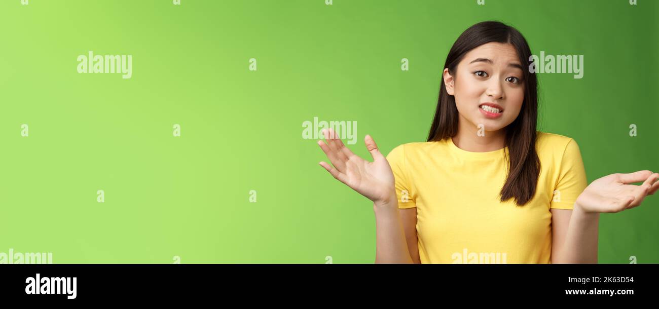 Confused cute apologizing asian girl shrugging hands spread sideways ...