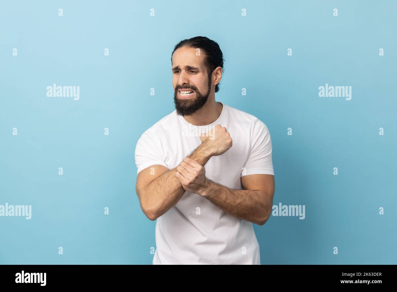 Portrait of sick man with beard wearing white T-shirt standing with ...