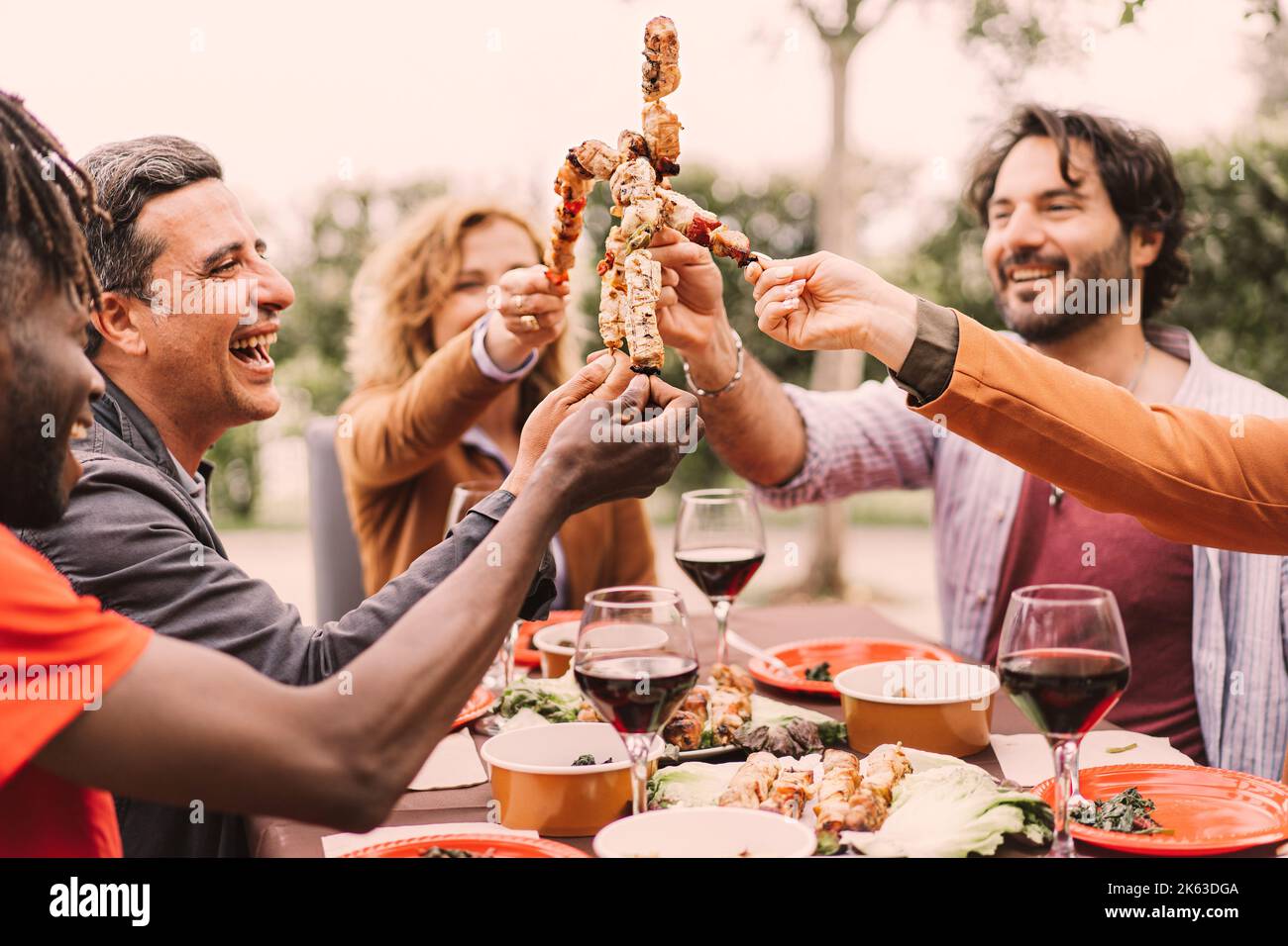 Outdoor shot of multiethnic friends enjoying barbecue party in garden ...
