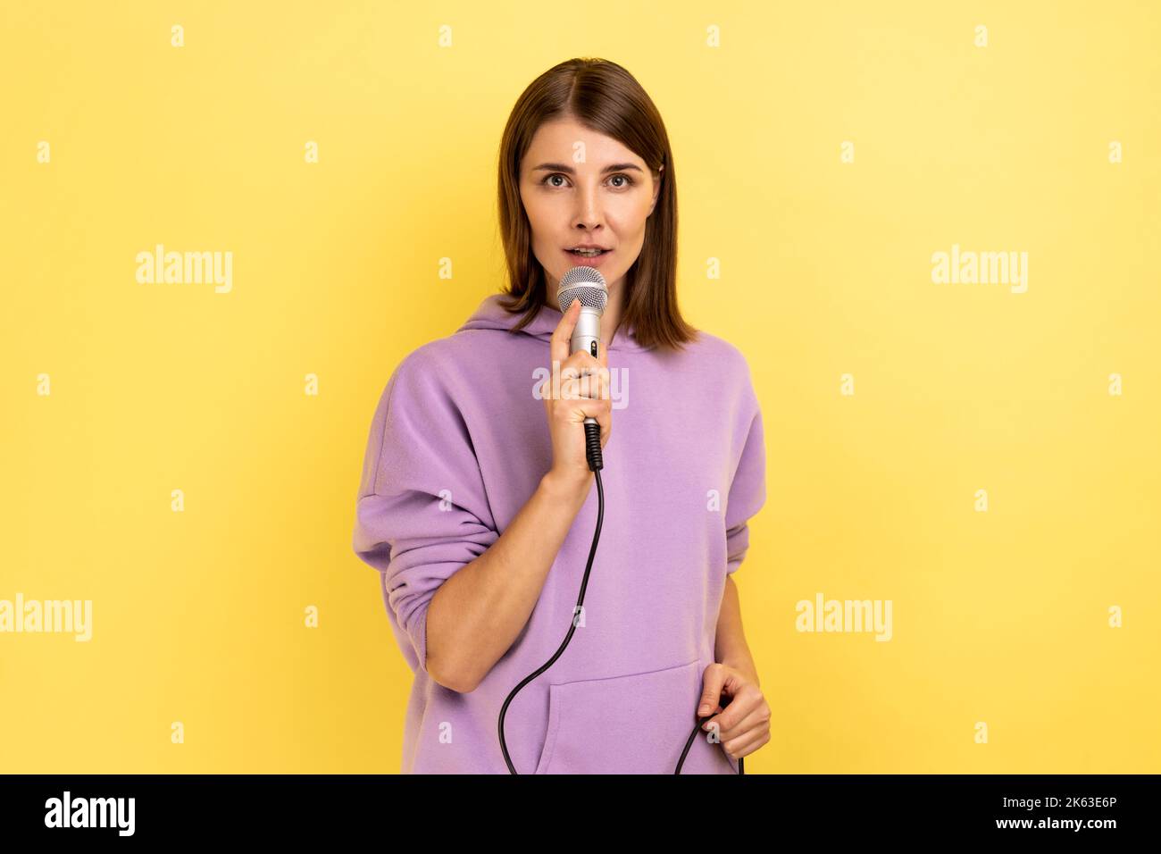 Young adult beautiful woman reporter holding microphone, reporting and ...