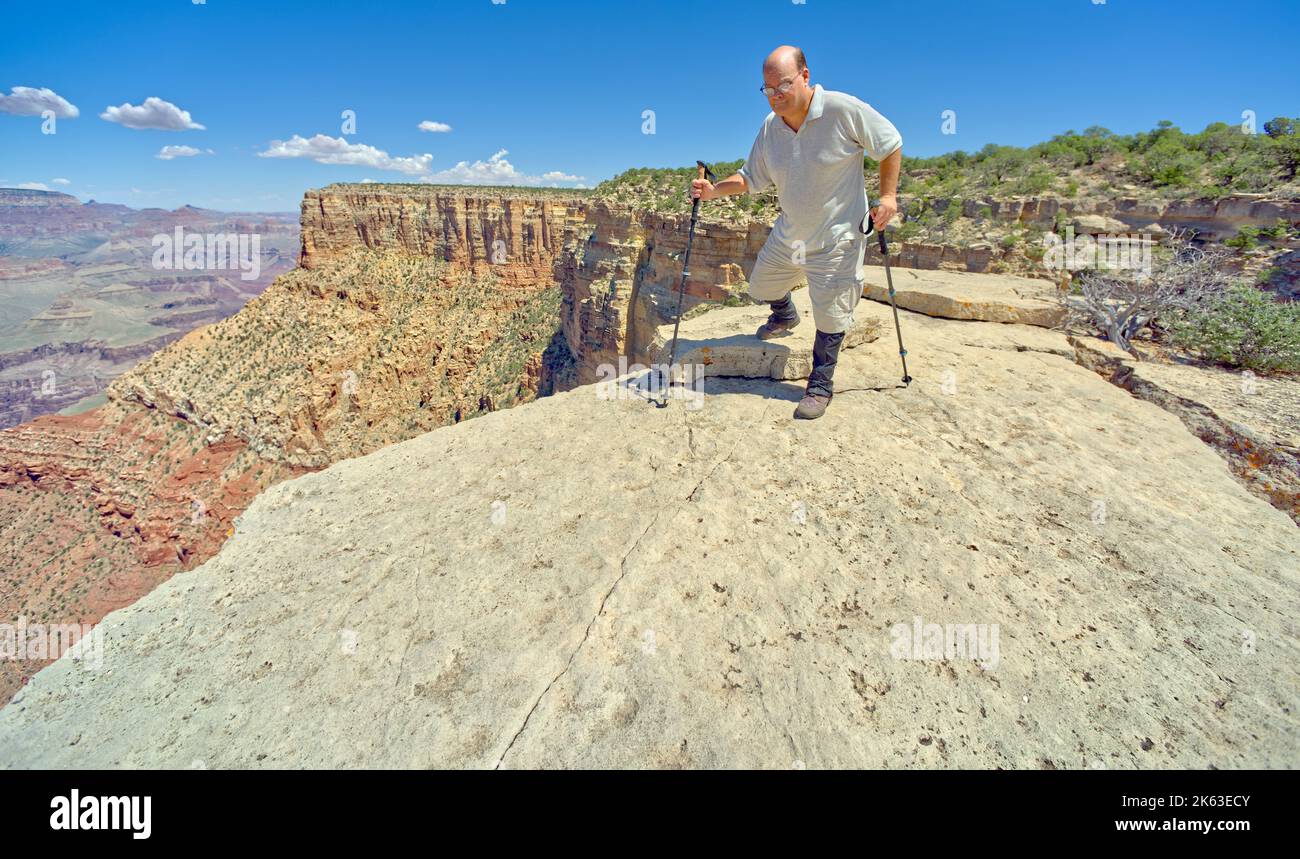 A hiker on the edge of a cliff between Moran Point and Zuni Point at ...