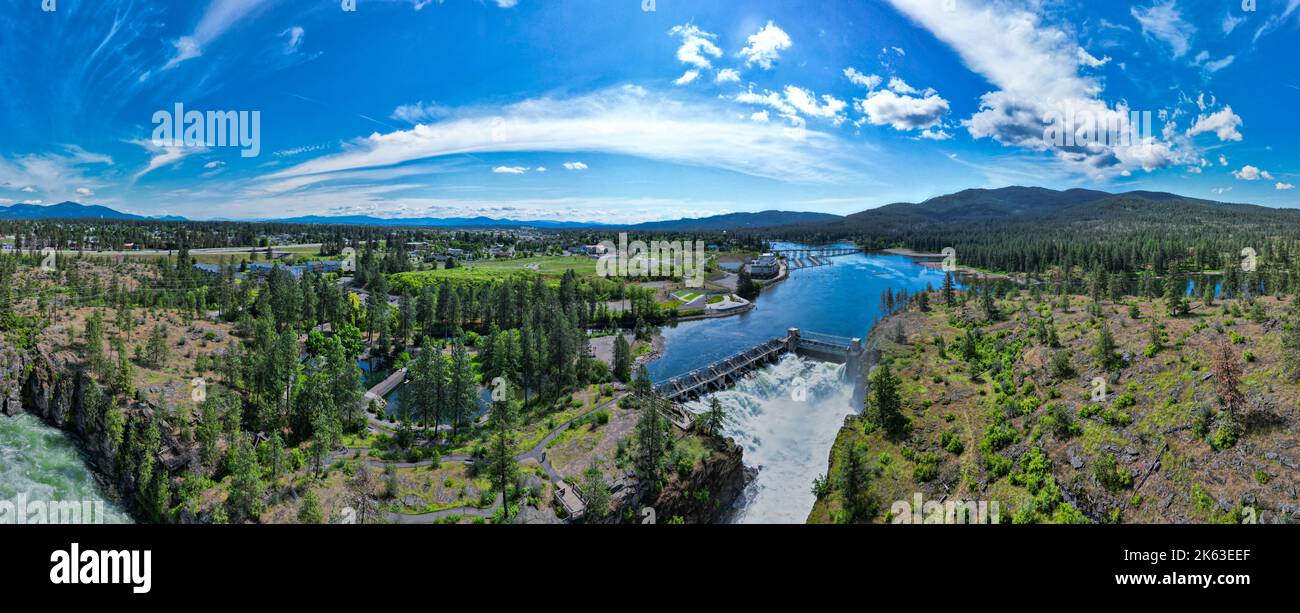 An arial view of Post Falls Dam surrounded by trees with blue sky in ...