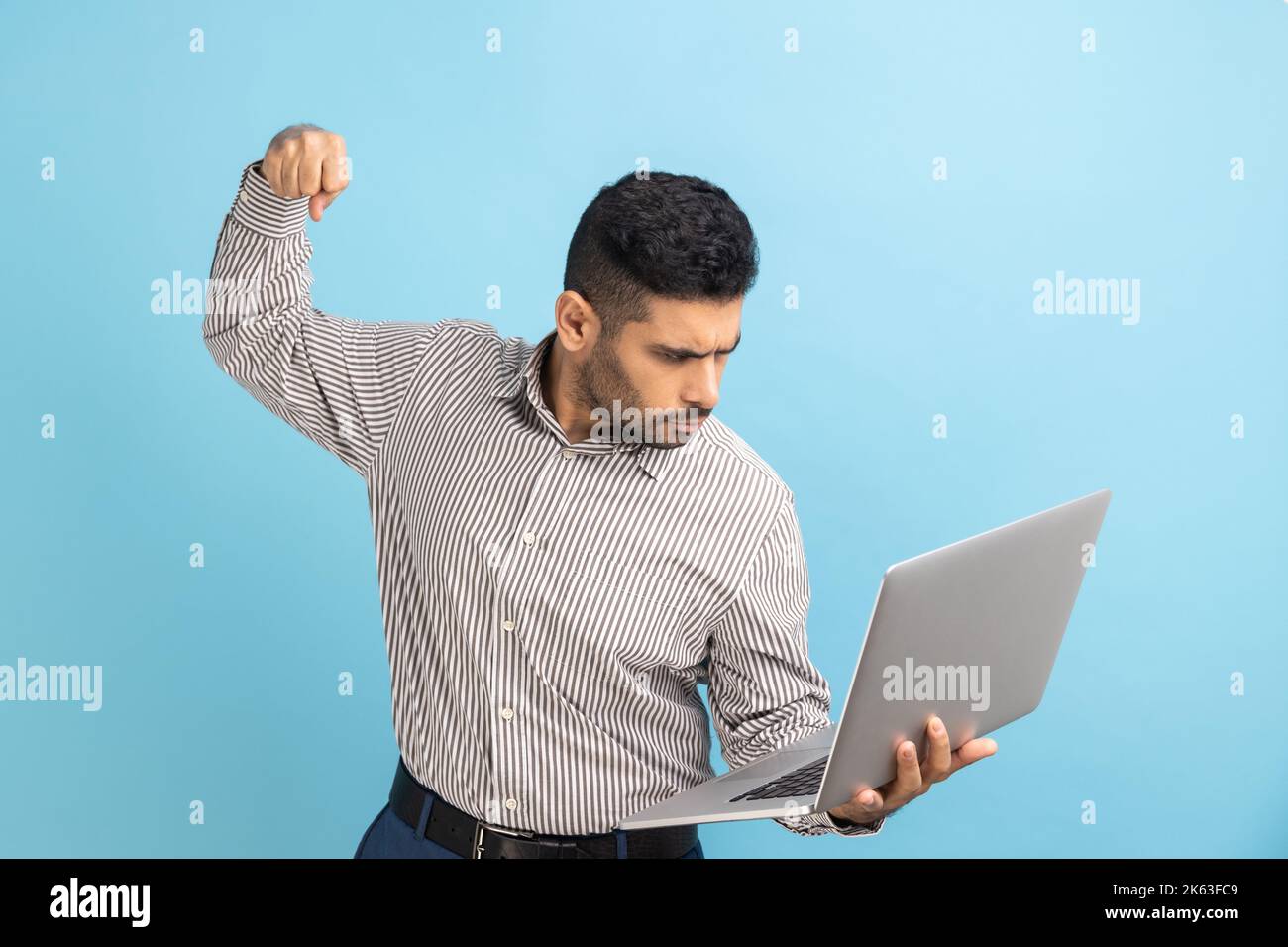 Angry businessman punching laptop screen, looking with mad expression ...