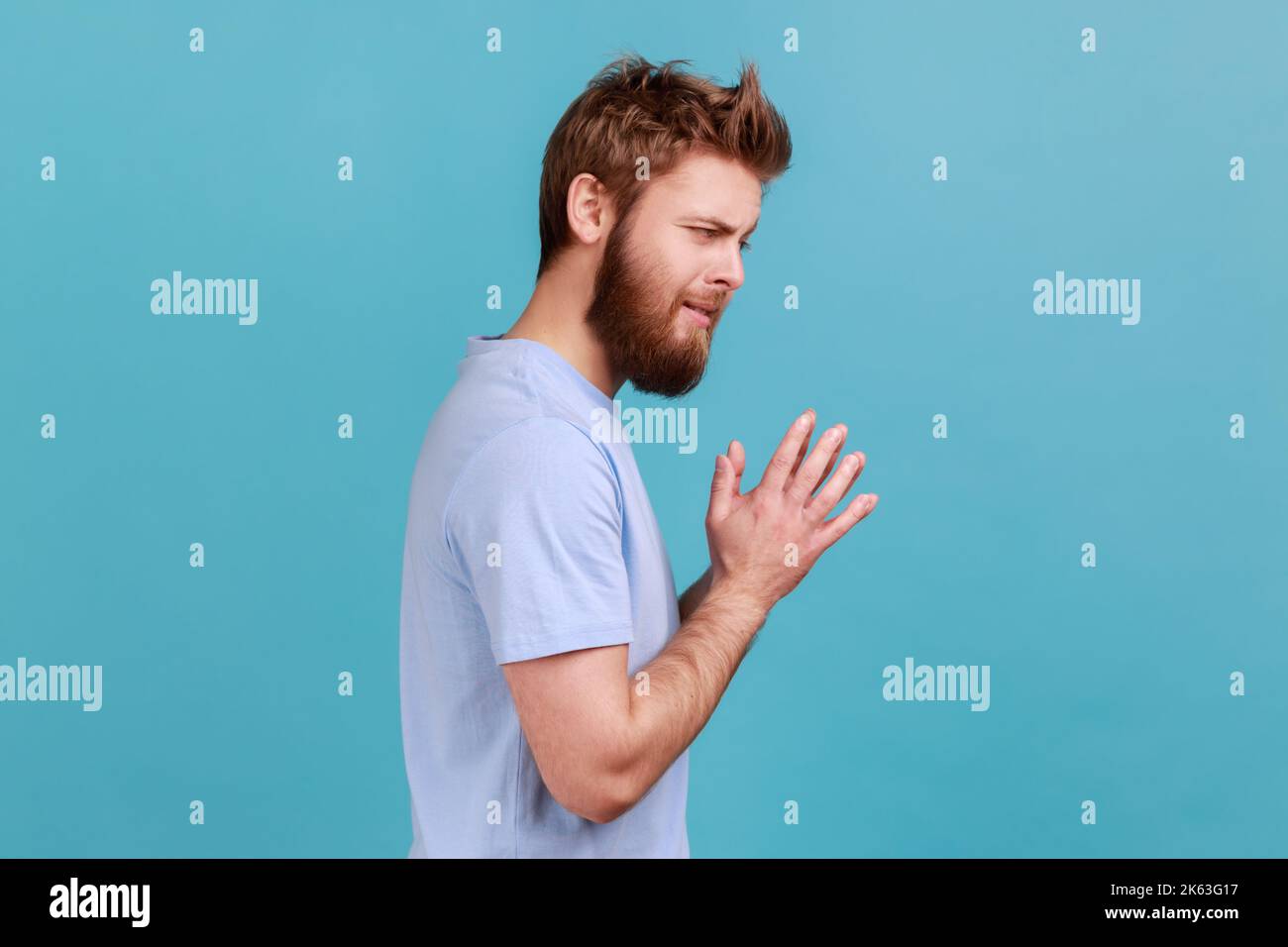 Side view of cunning bearded man schemes something keeps hands together ...