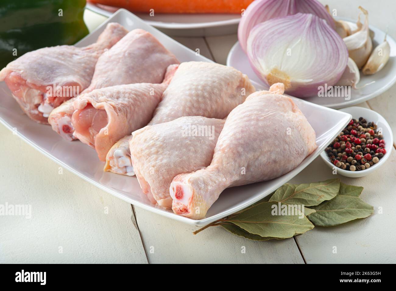 Raw chicken legs with vegetables for cooking on the kitchen table Stock ...