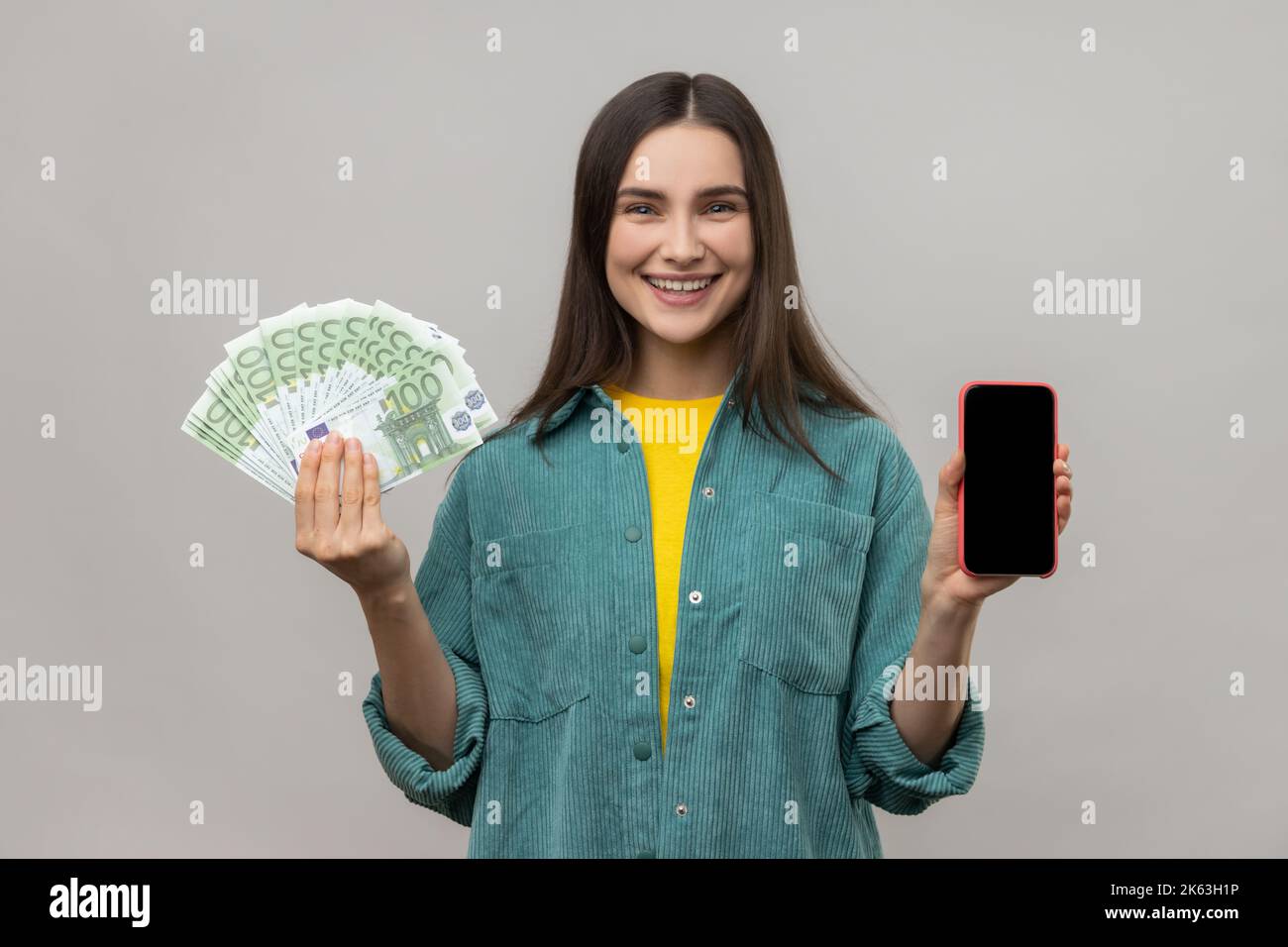 Happy positive rich woman holding euro banknotes and phone with blank ...