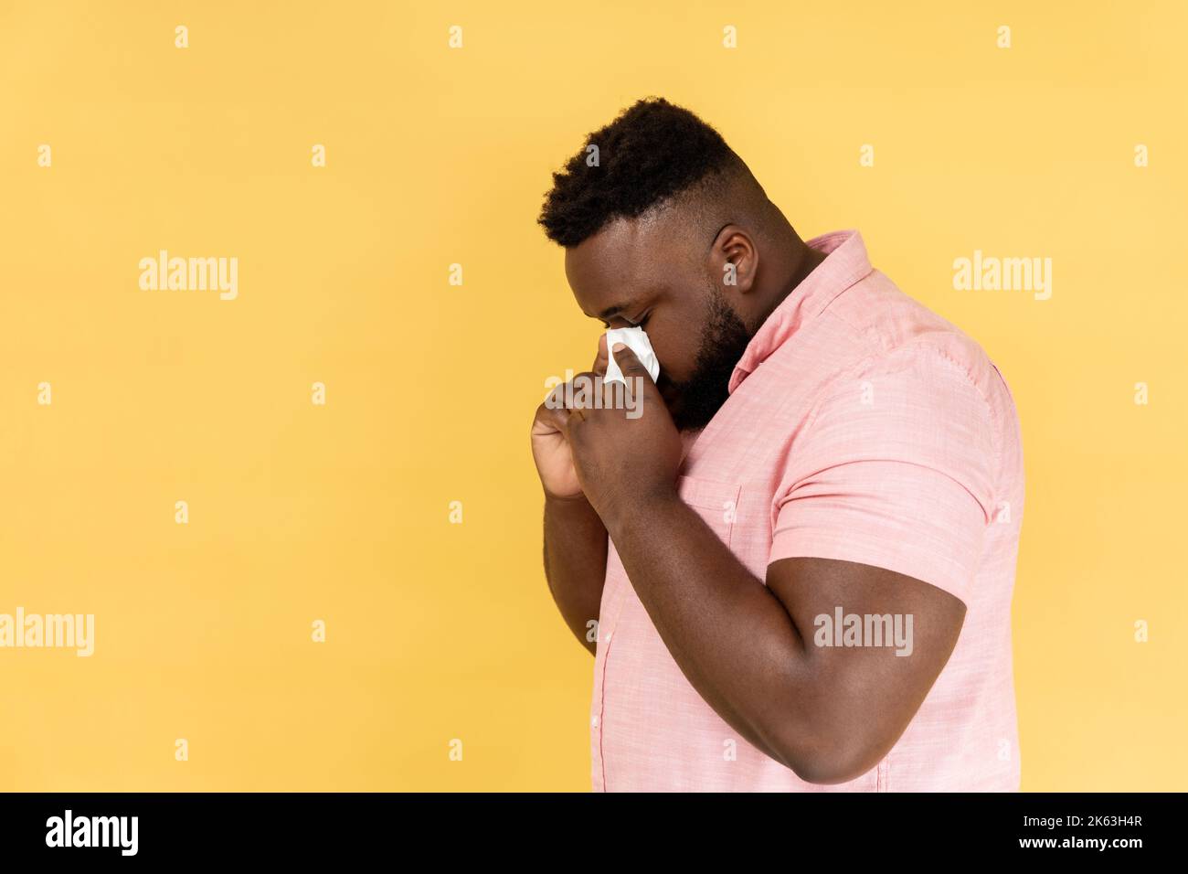 Side view portrait of man wearing pink shirt hiding face in hand with ...