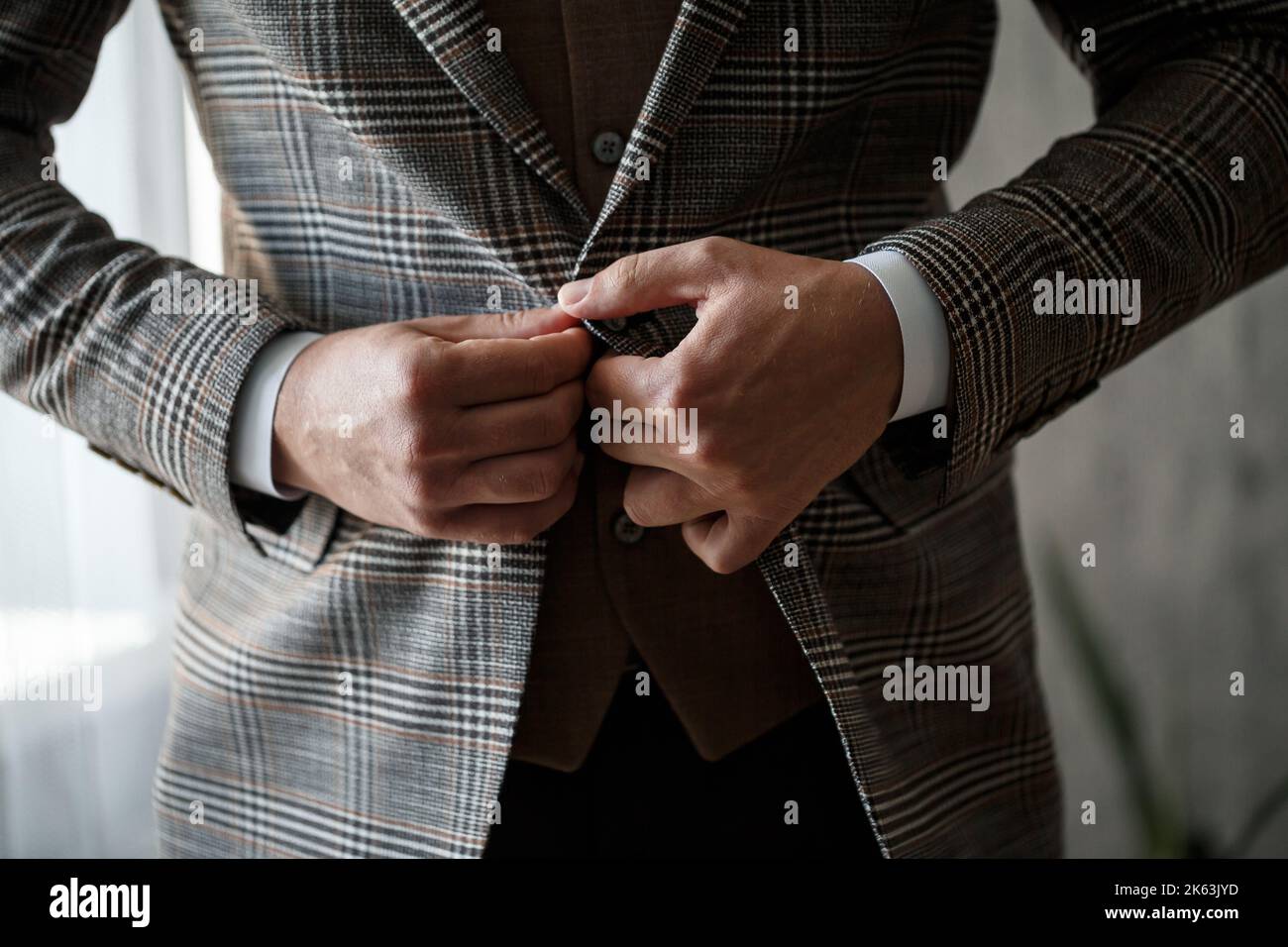 Stylish man groom buttoning a button on his jacket Stock Photo - Alamy