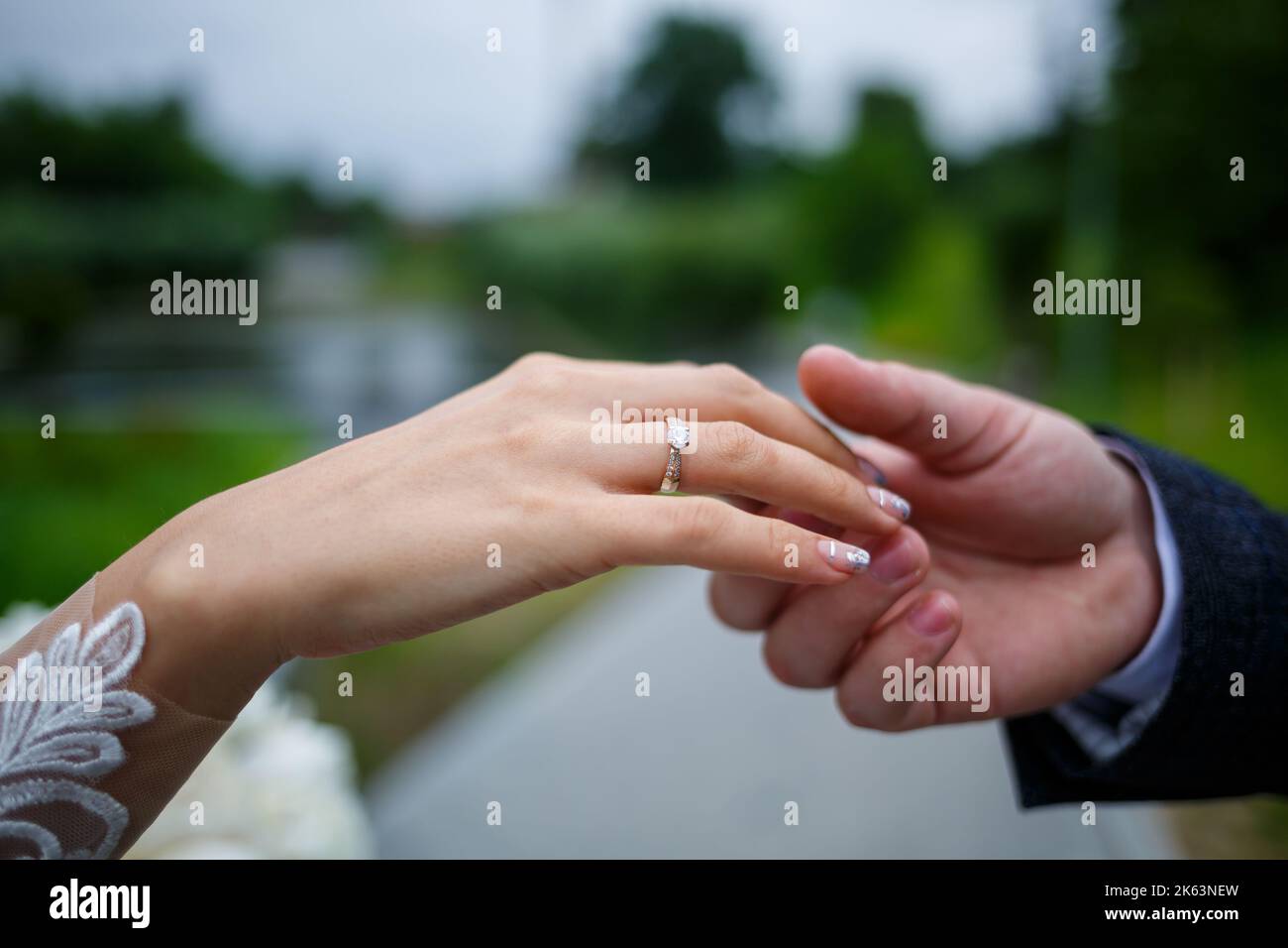 Gentle female hands of the bride with a gold wedding ring on the ring ...