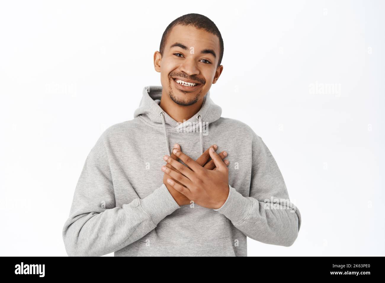 Portrait of caring smiling guy holds hands on heart, looking grateful ...