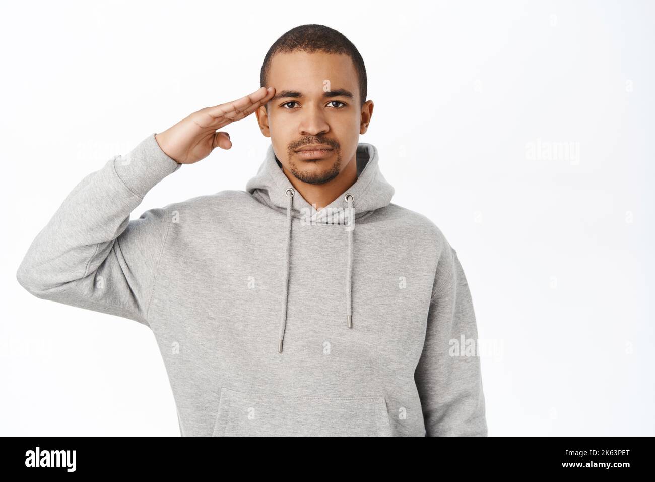 Image of young man saluting, holding hand near forehead, army greeting ...