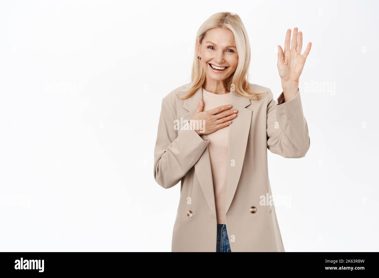 Smiling mature blond woman, saying hello, introduce herself, hi gesture ...