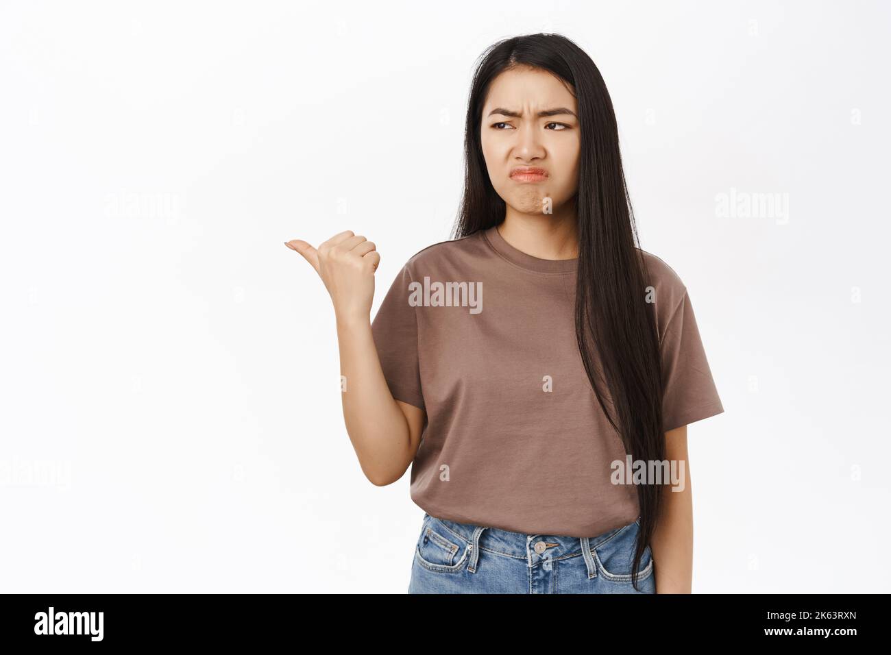 Jealous asian girl, disappointed woman pointing finger left, grimacing ...