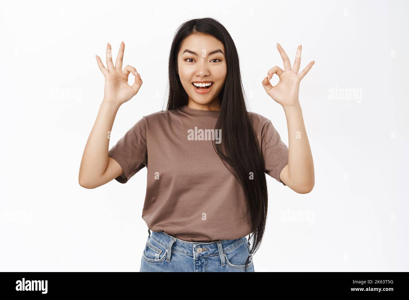 Portrait of cute asian girl shows okay, ok, excellent gesture, smiling ...