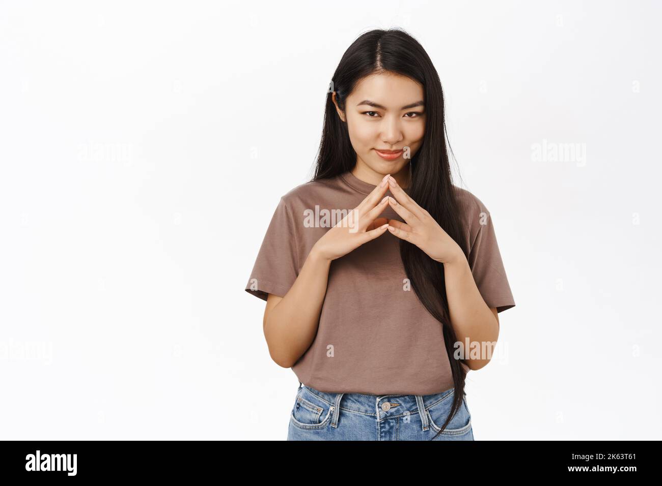 Image of smiling coy asian girl, planning, scheming, steeple fingers ...