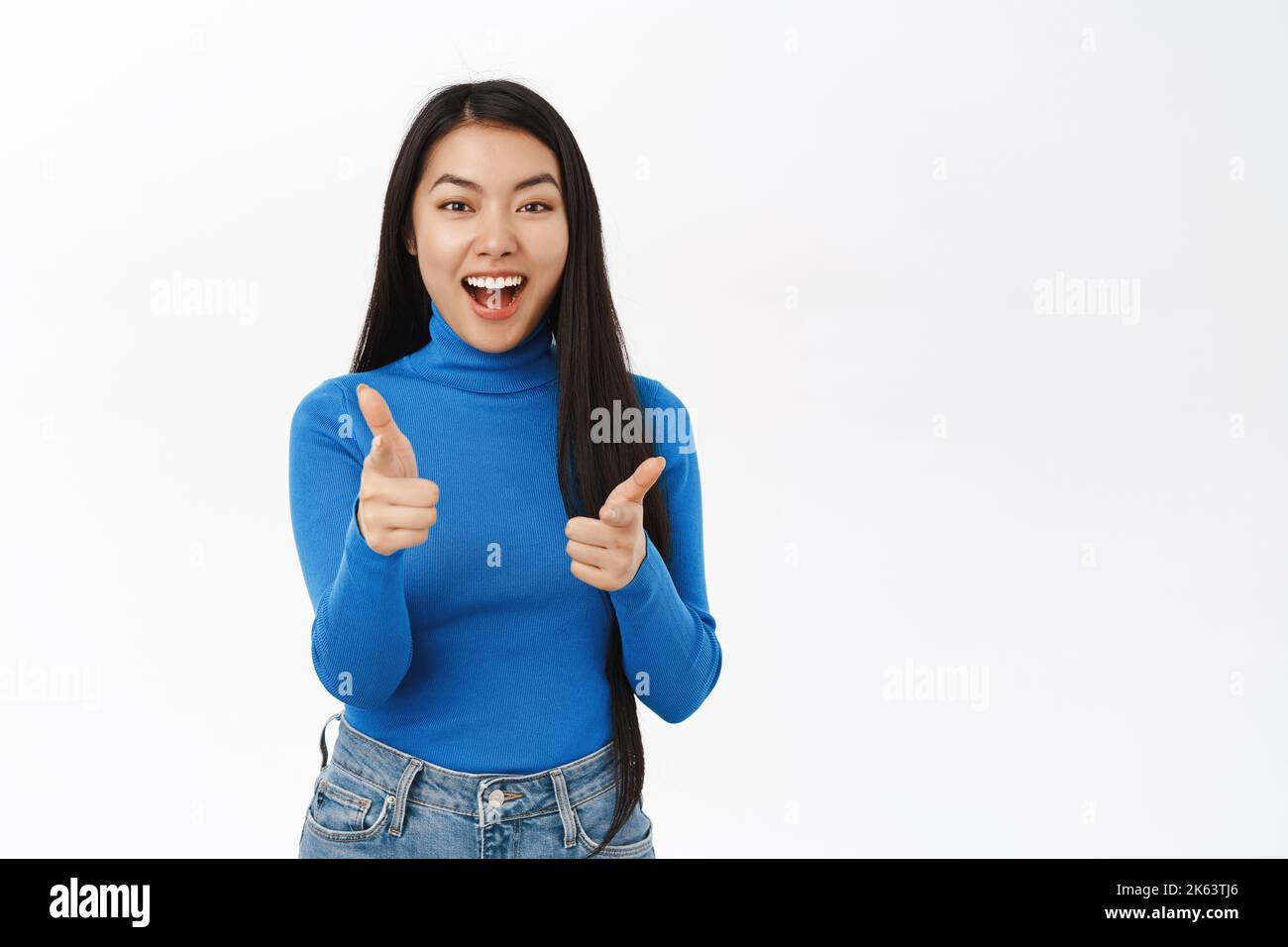 Portrait of enthusiastic beautiful female model, pointing fingers at ...