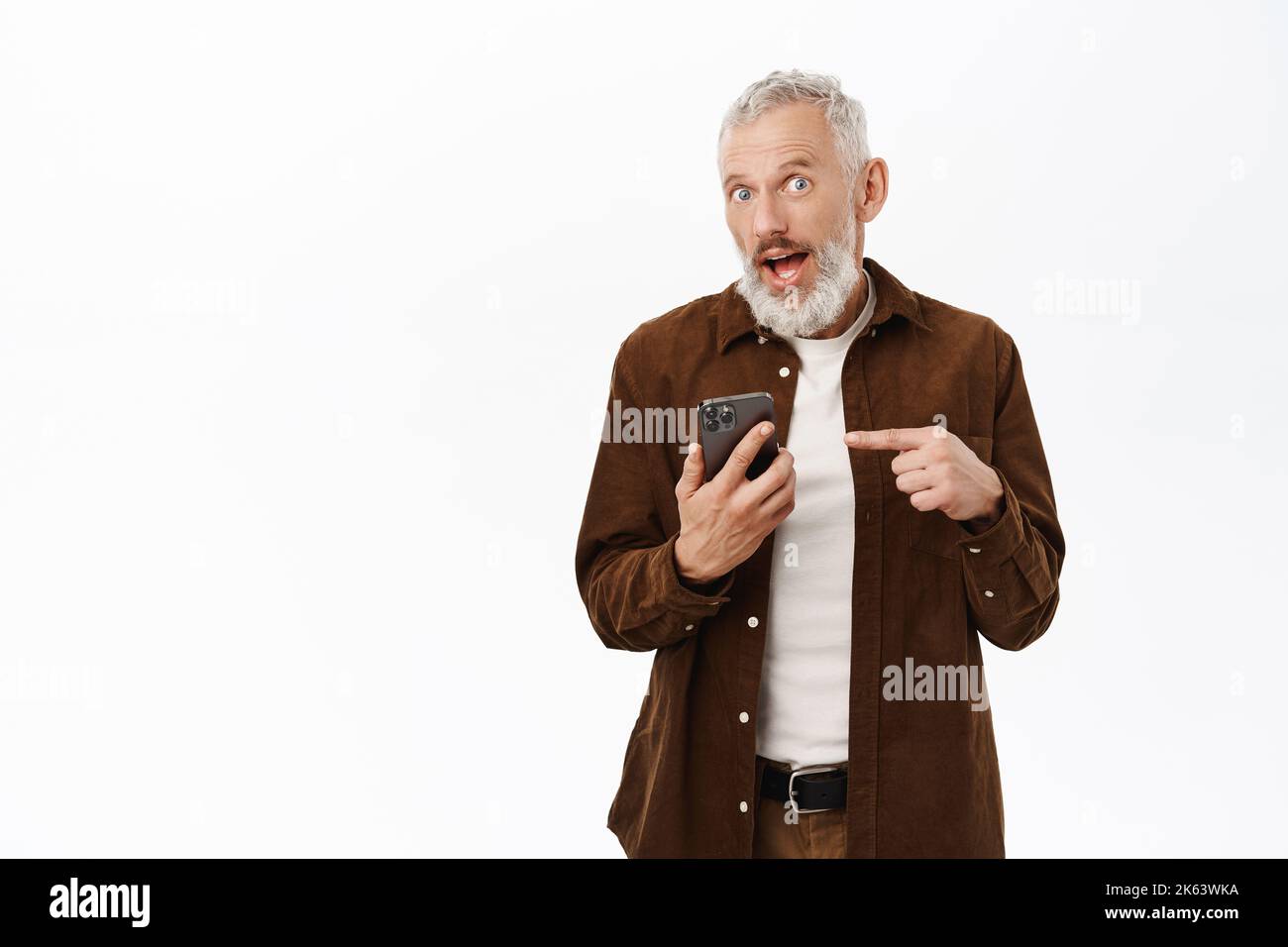 Handsome old man, dad with grey hair, pointing finger at mobile phone ...