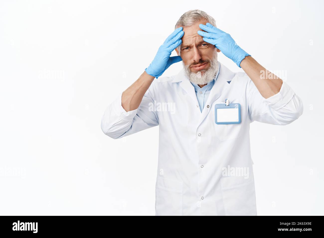 Tired senior male doctor, holding hands on head, migraine, distressed ...