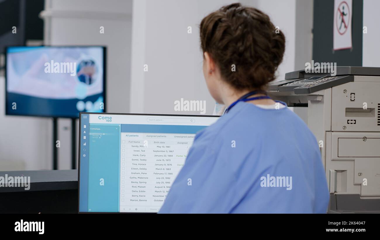 Medical nurse checking exam appointments on computer at hospital ...
