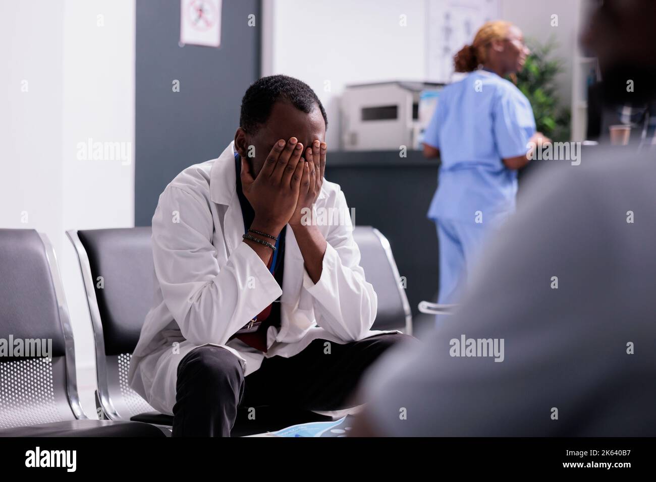 Distressed unhappy doctor sitting in clinic lobby, feeling overworked ...
