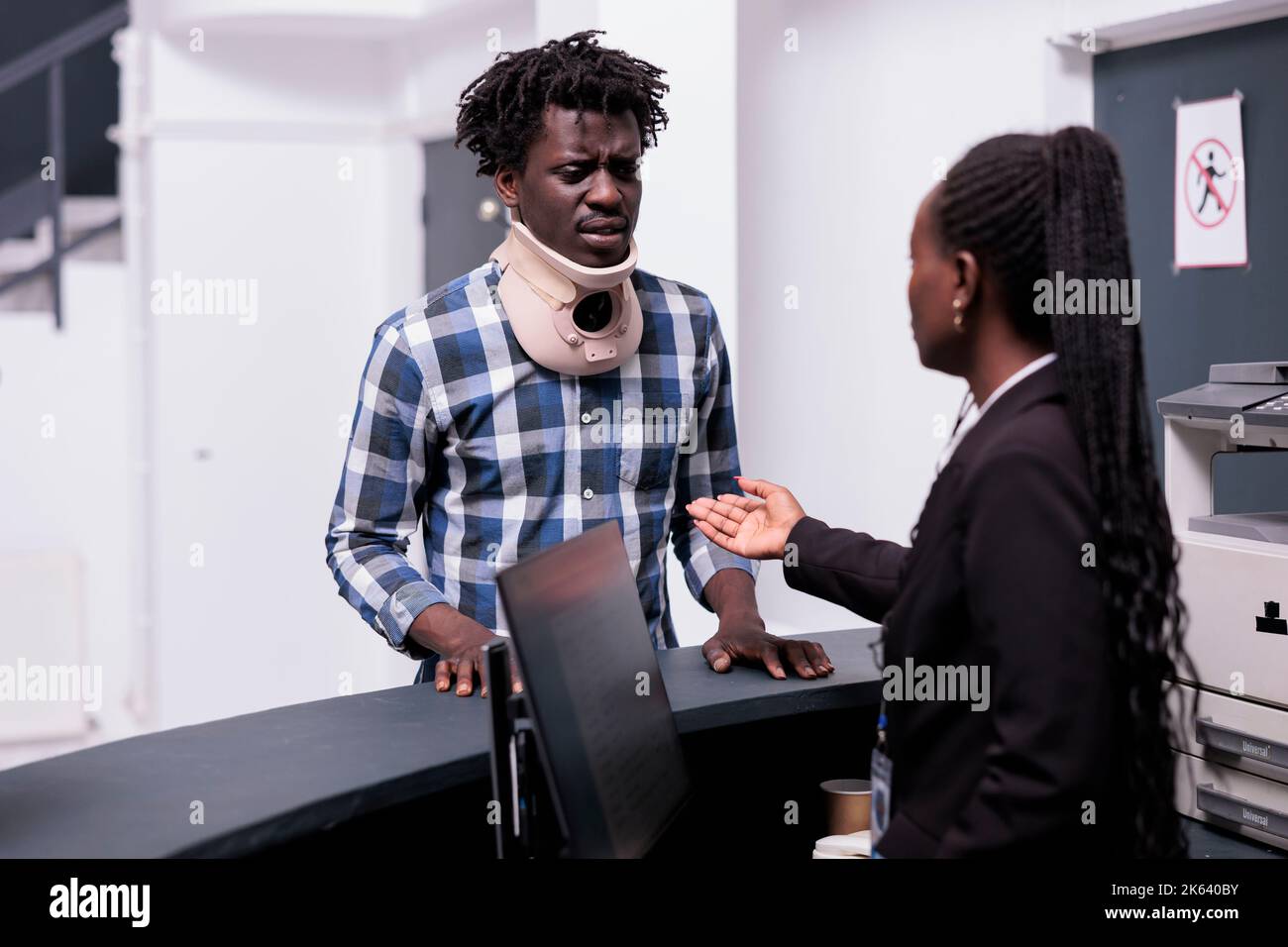 Man with neck collar at reception counter, asking for help and being in ...