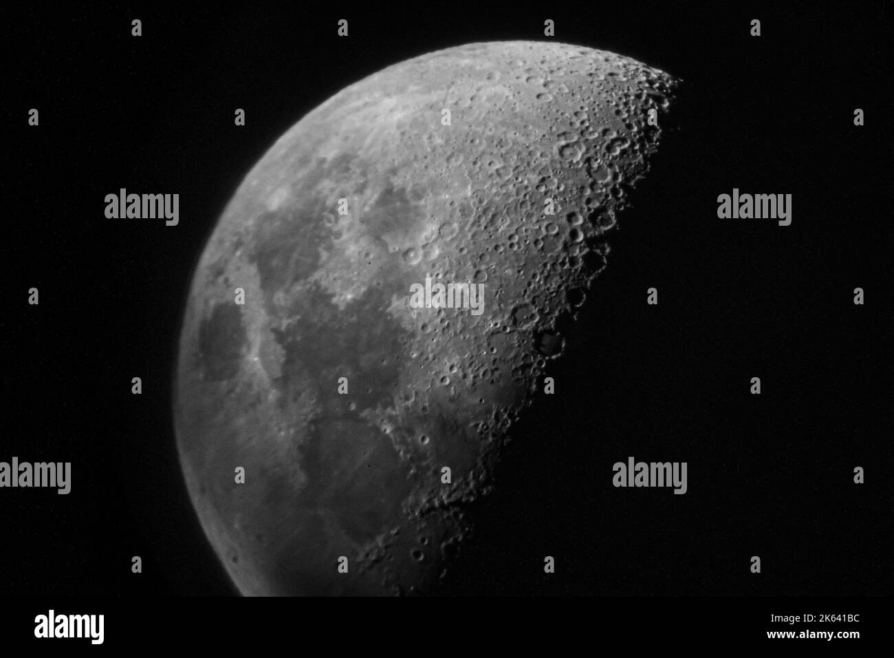 A closeup grayscale of a half moon with visible lunar craters Stock ...