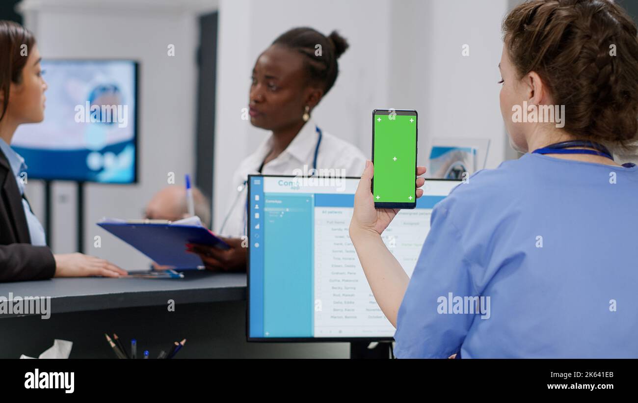 Medical assistant holding smartphone with greenscreen display at ...