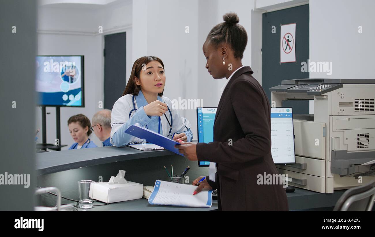 Diverse medical workers analyzing checkup papers at hospital reception ...