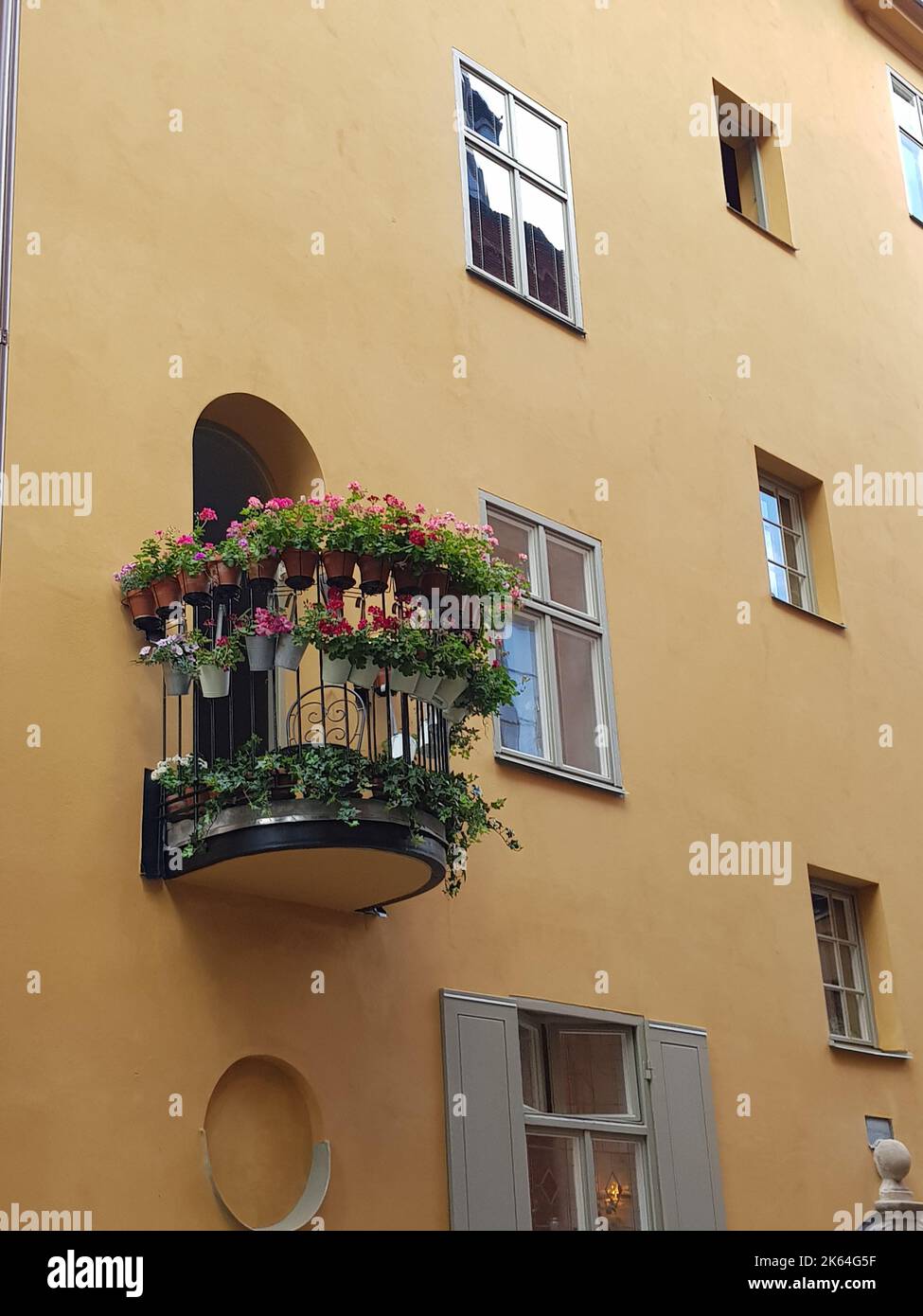 A vertical shot of a yellow residential building with a balcony full of ...