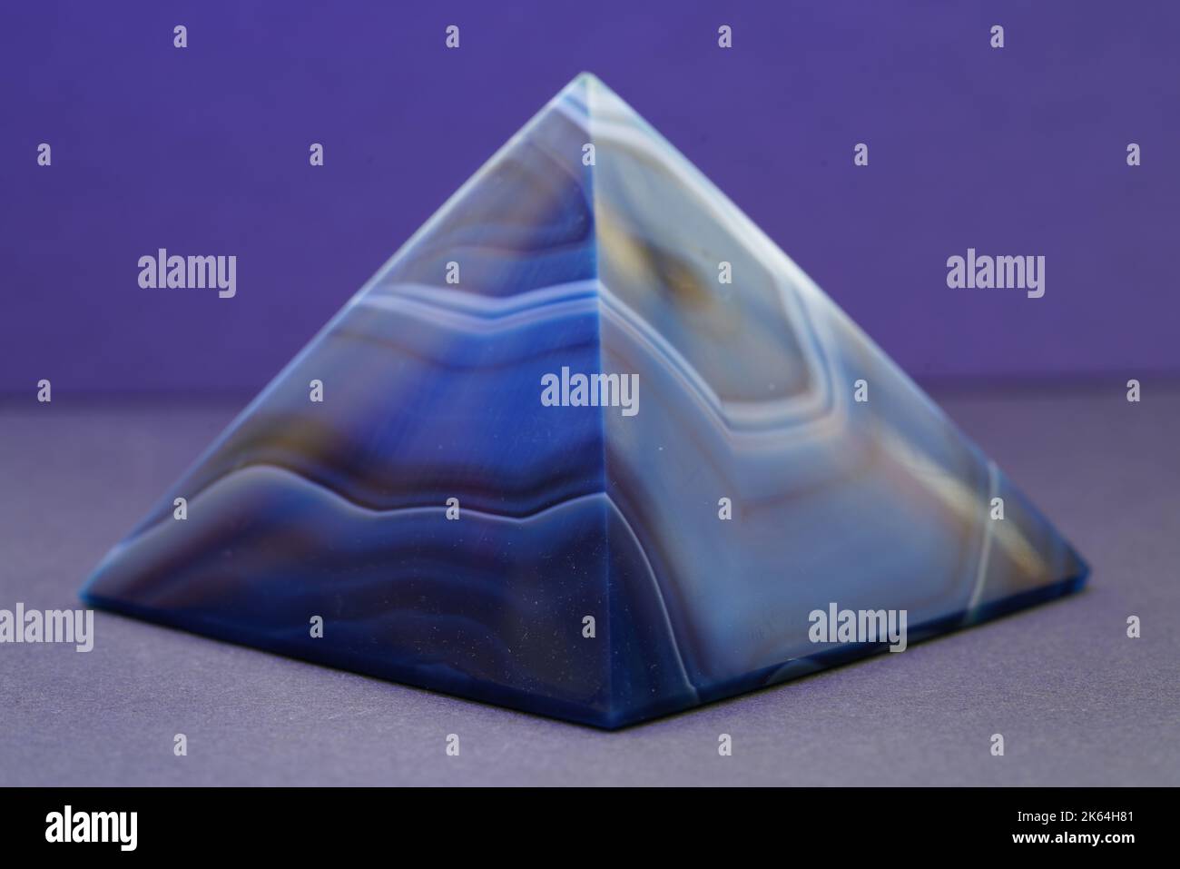 A closeup shot of a blue marble pyramid with a purple background Stock ...