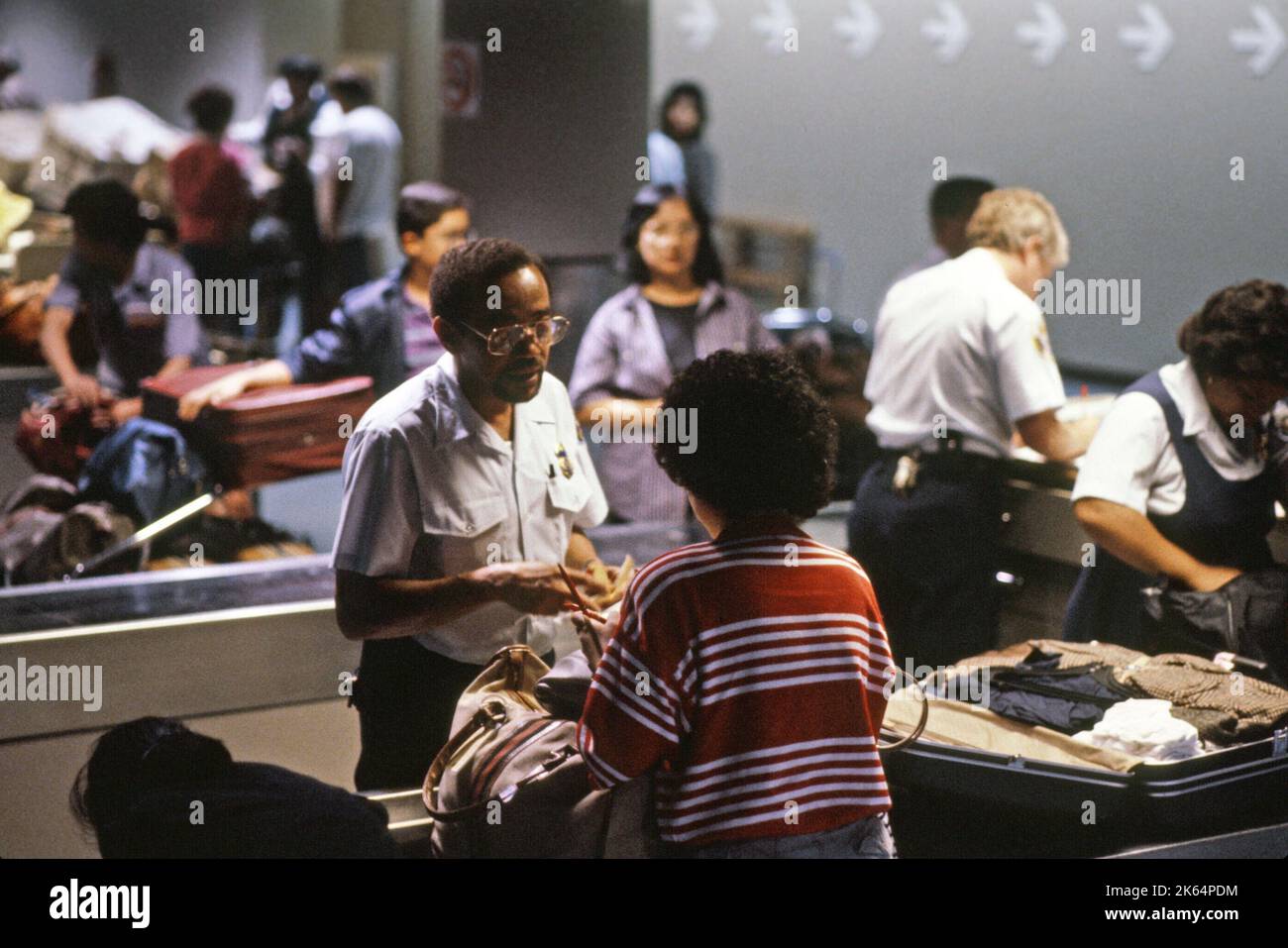 US Customs officers inspect the luggage of multiracial arriving ...