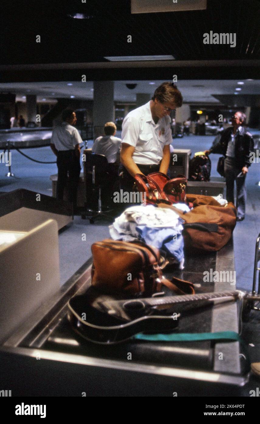 US Customs officers inspect the luggage of multiracial arriving ...