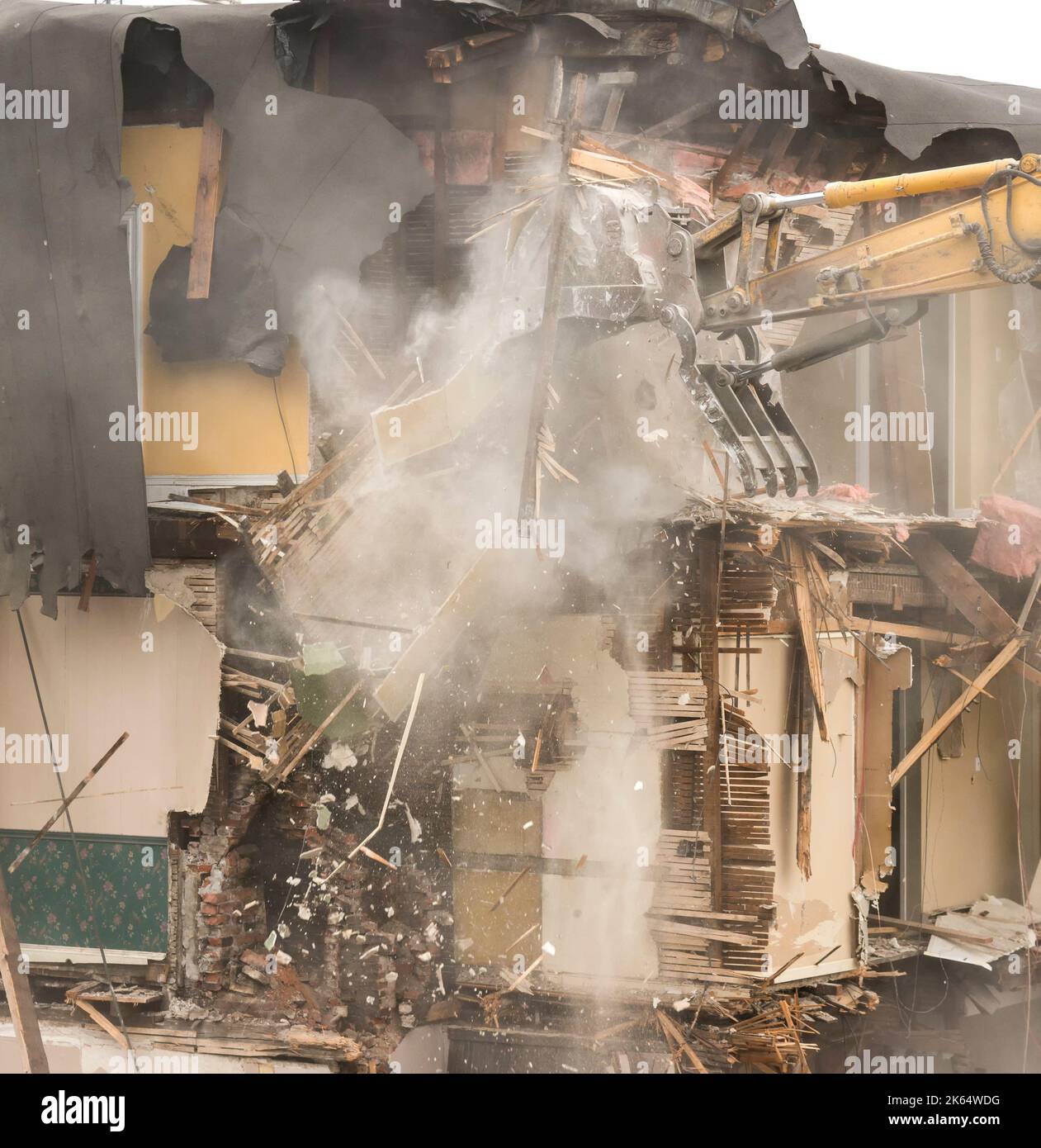 Demolishing a building with a large backhoe. Overcast day. Lots of dust ...