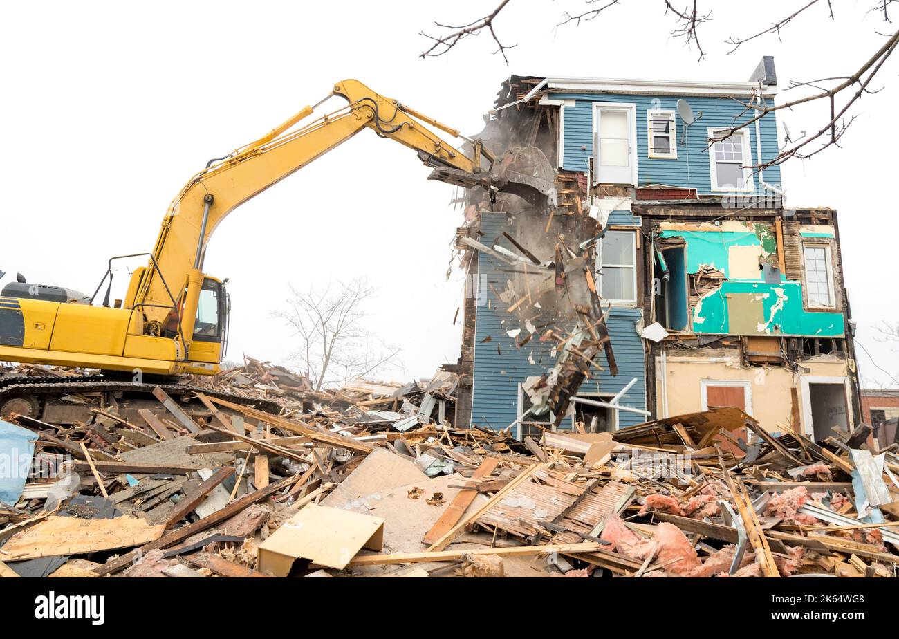 Demolishing a building with a large backhoe. Overcast day. Air is dusty ...
