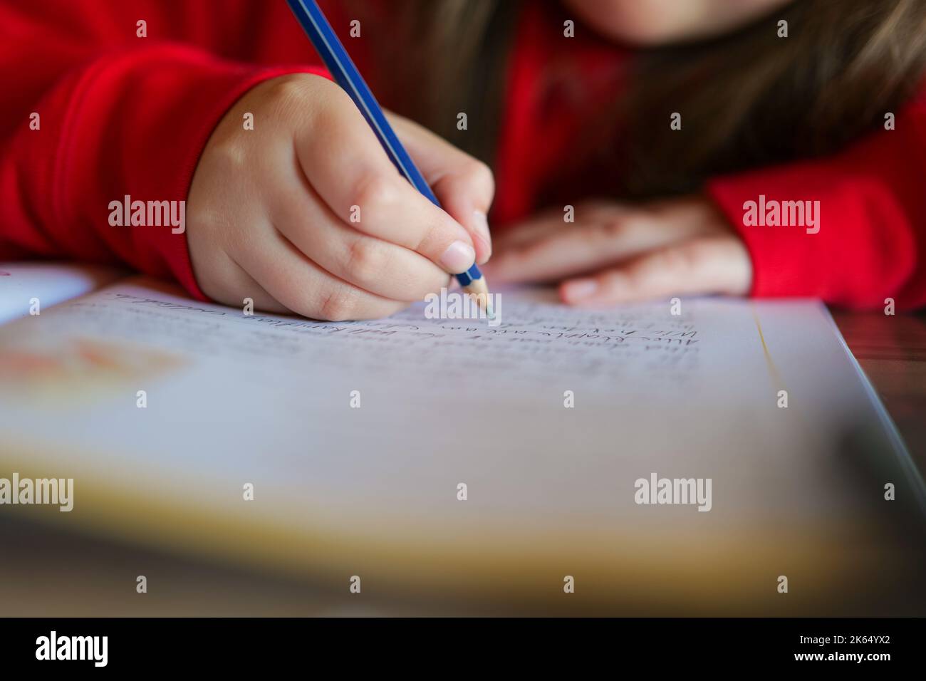 schoolgirl does her homework. child writes with a pencil in a notebook ...