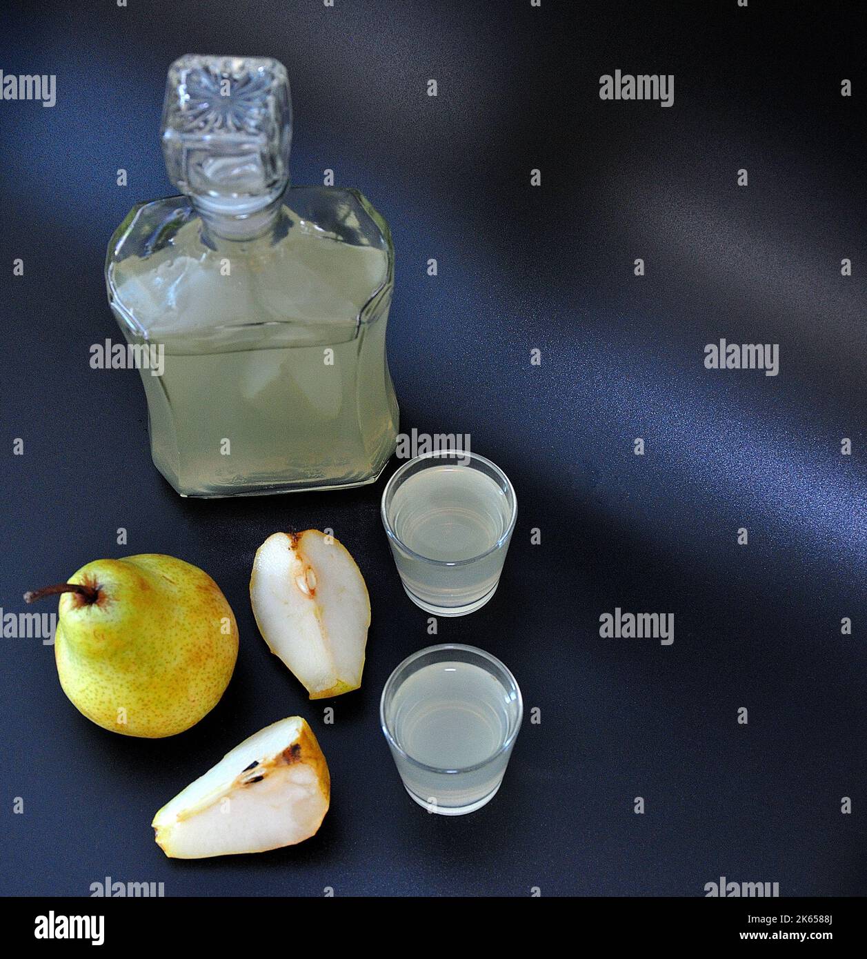 Pear Calvados on a black background, alcohol in a bottle and two ...